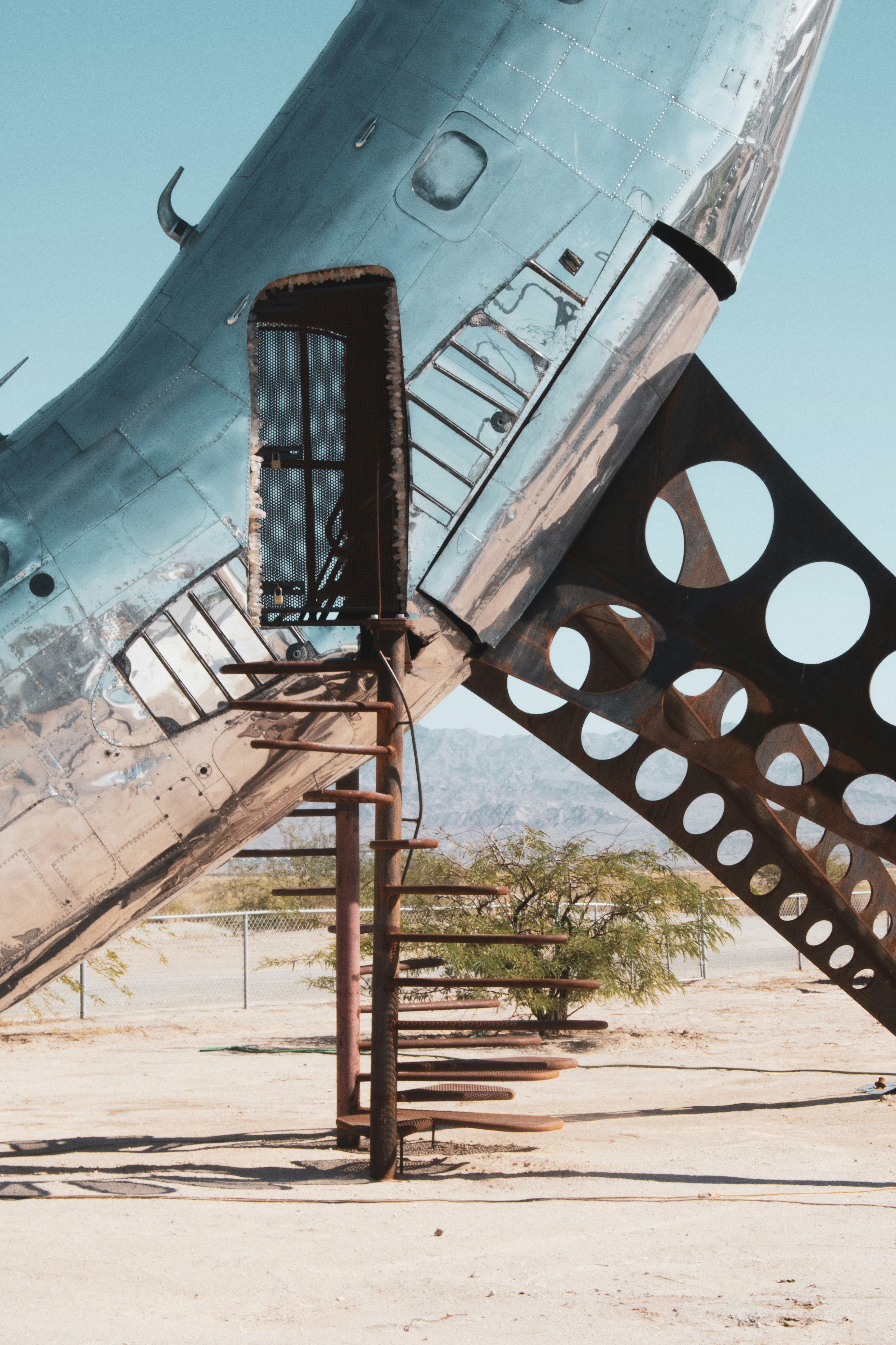 Desert Tilt: A Sun-bleached Aircraft Wreck Emerges with a Rusted Staircase