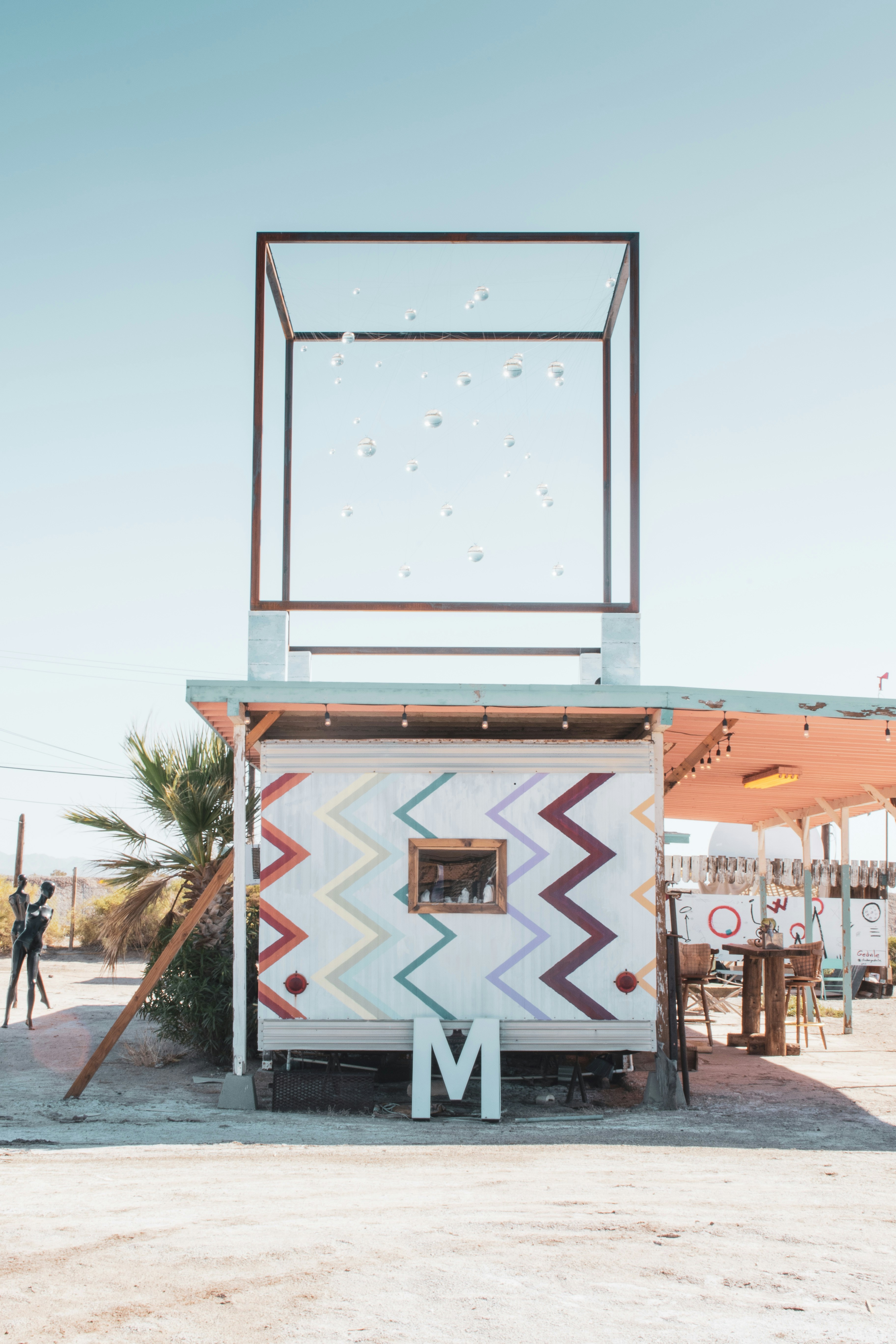 Desert Frame: A Minimal Metal Cube Anchors a Chevron-Kissed Kiosk