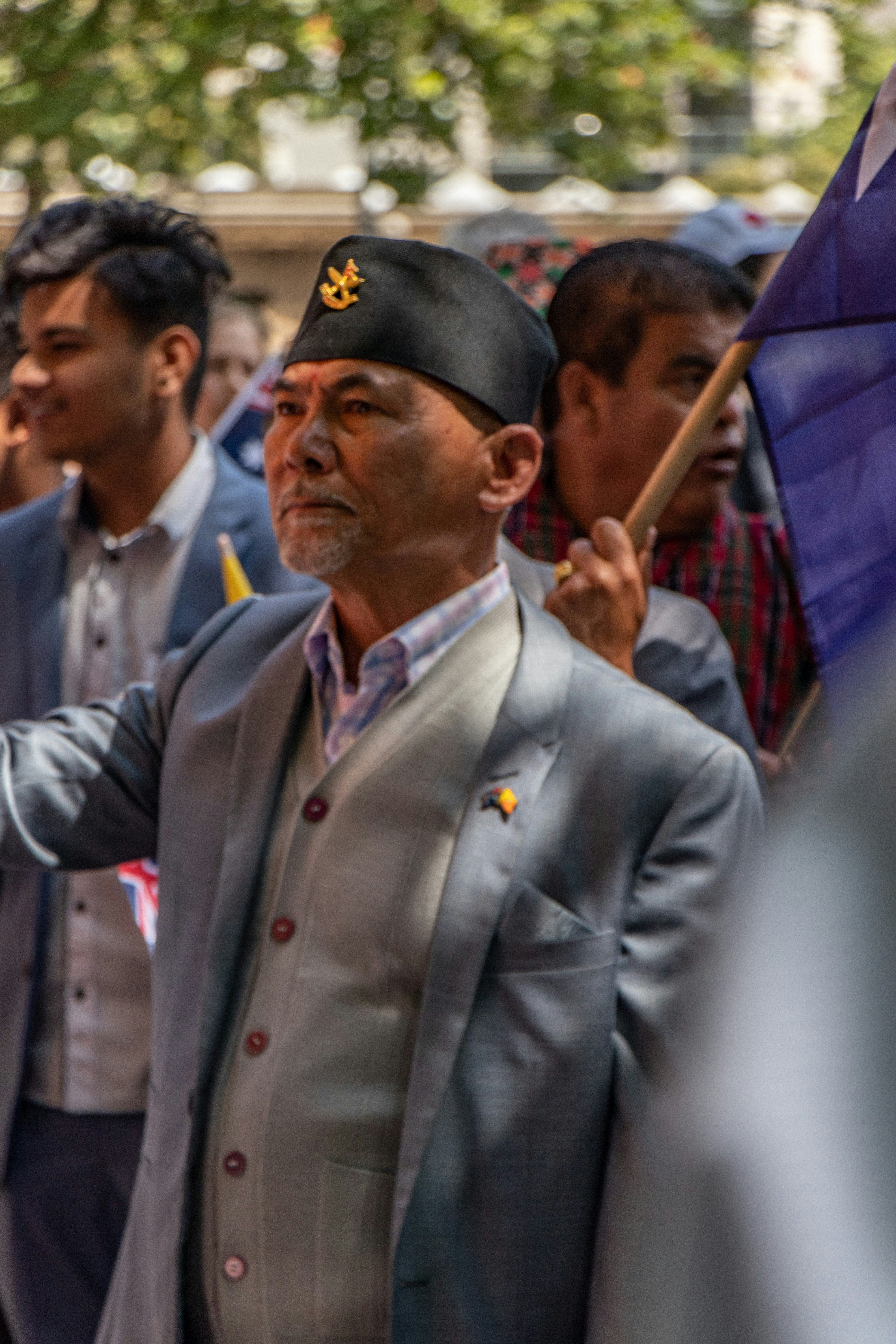 Flagbearer in a Gray Suit Leads a Daytime Procession