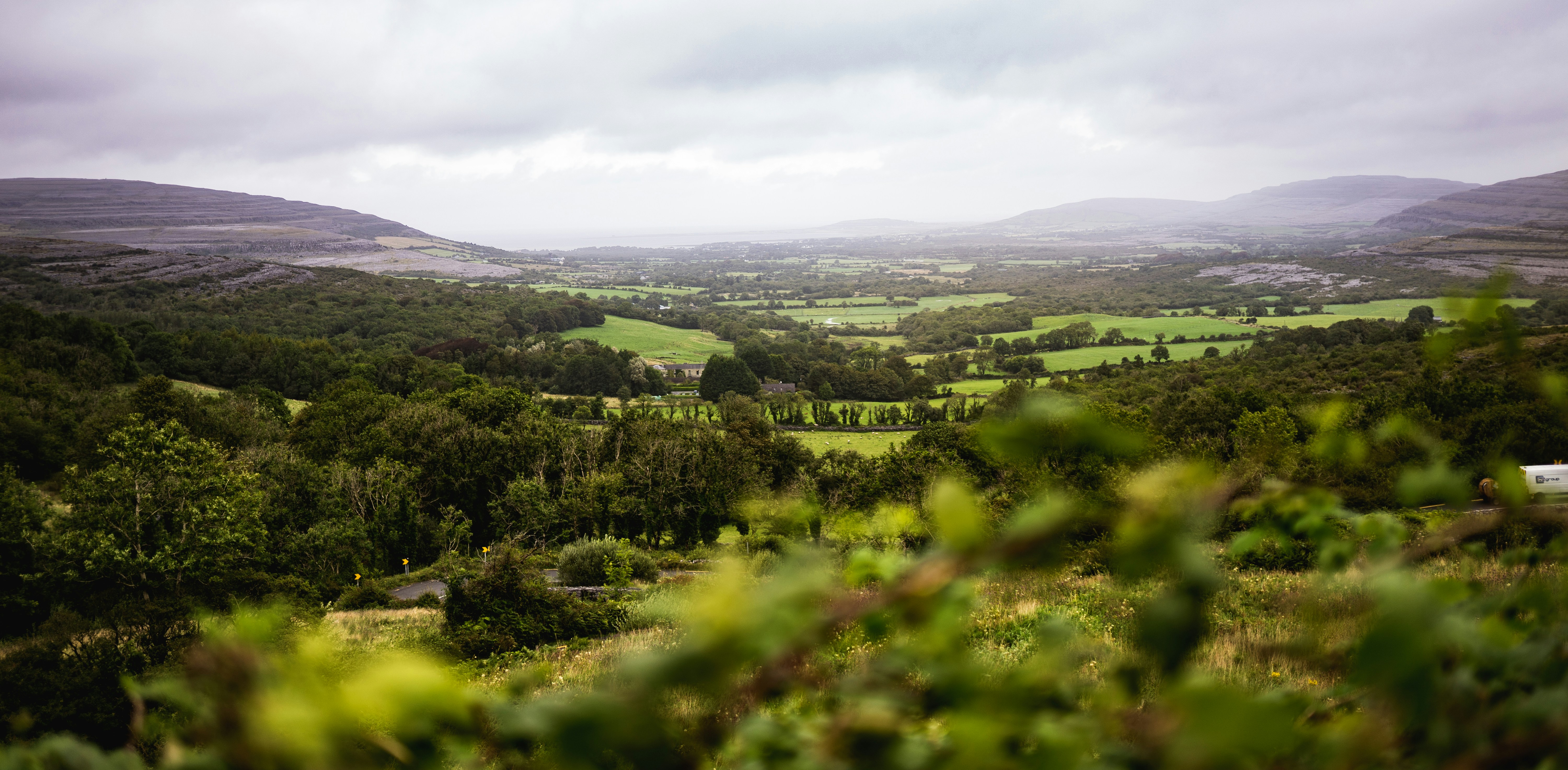 Expansive green fields and rolling hills under a cloudy sky in Connemara.