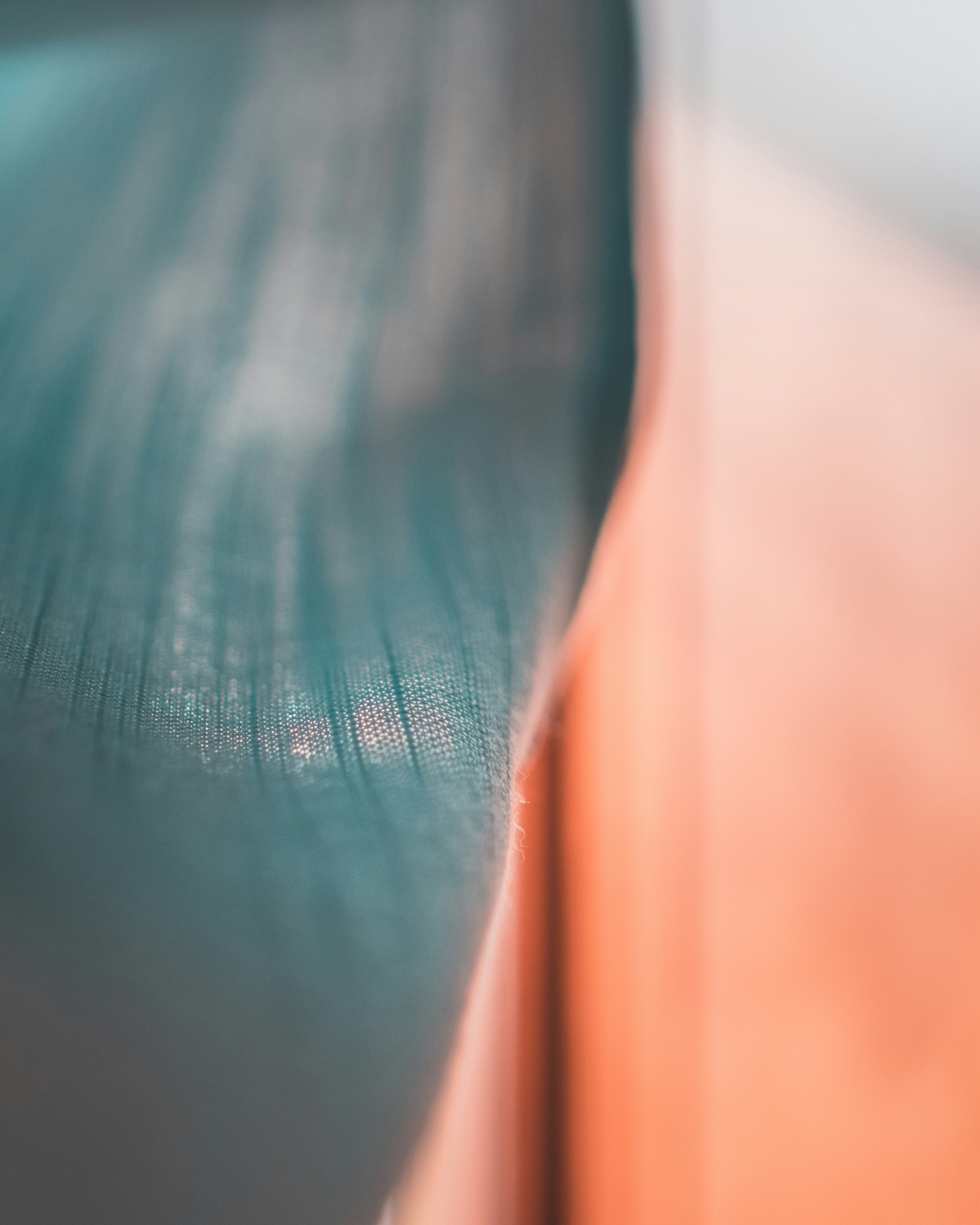 Teal textile and peach seam: a tactile macro embrace