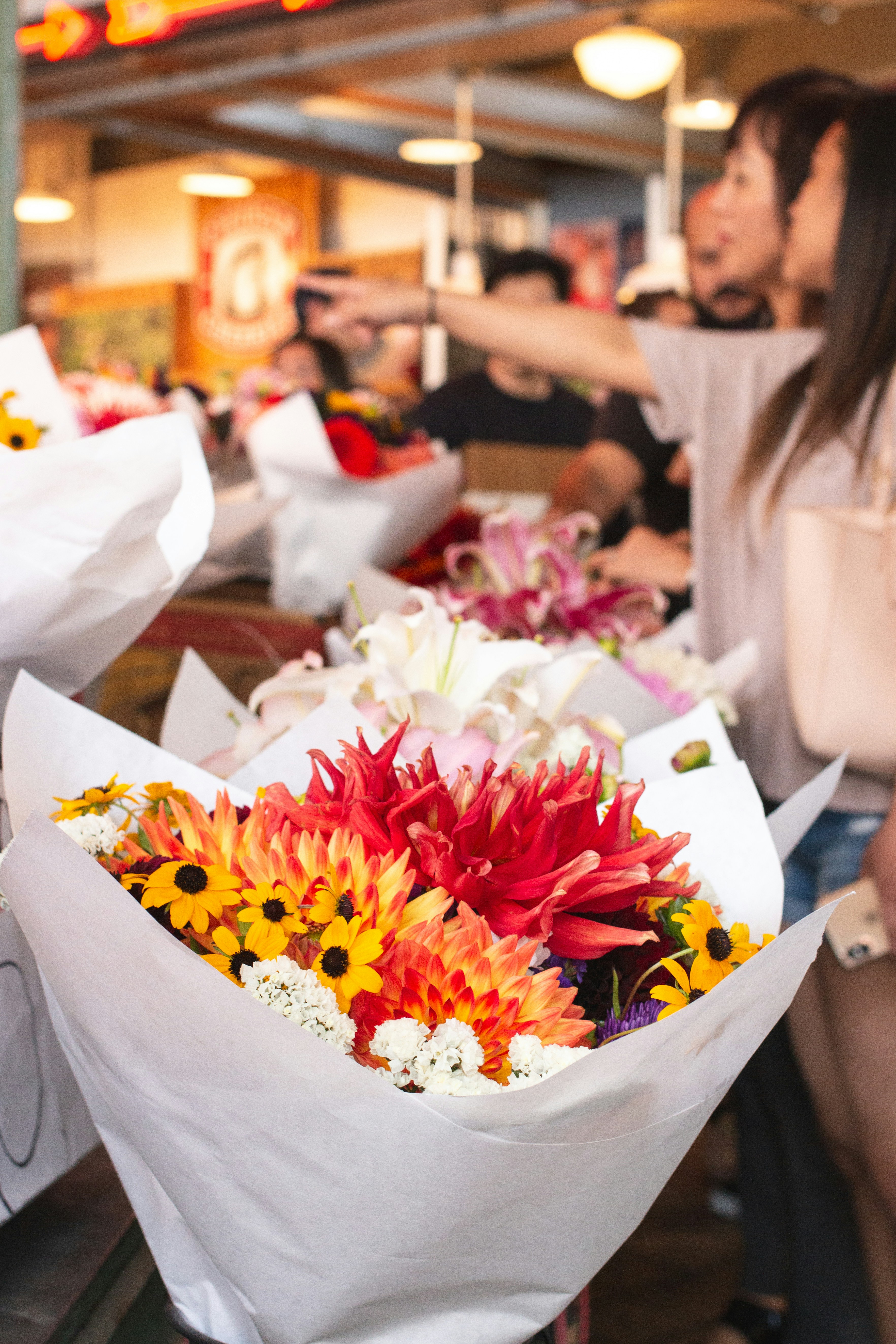 Colorful bouquets of flowers displayed at a bustling market, with shoppers engaged in selecting their favorites.
