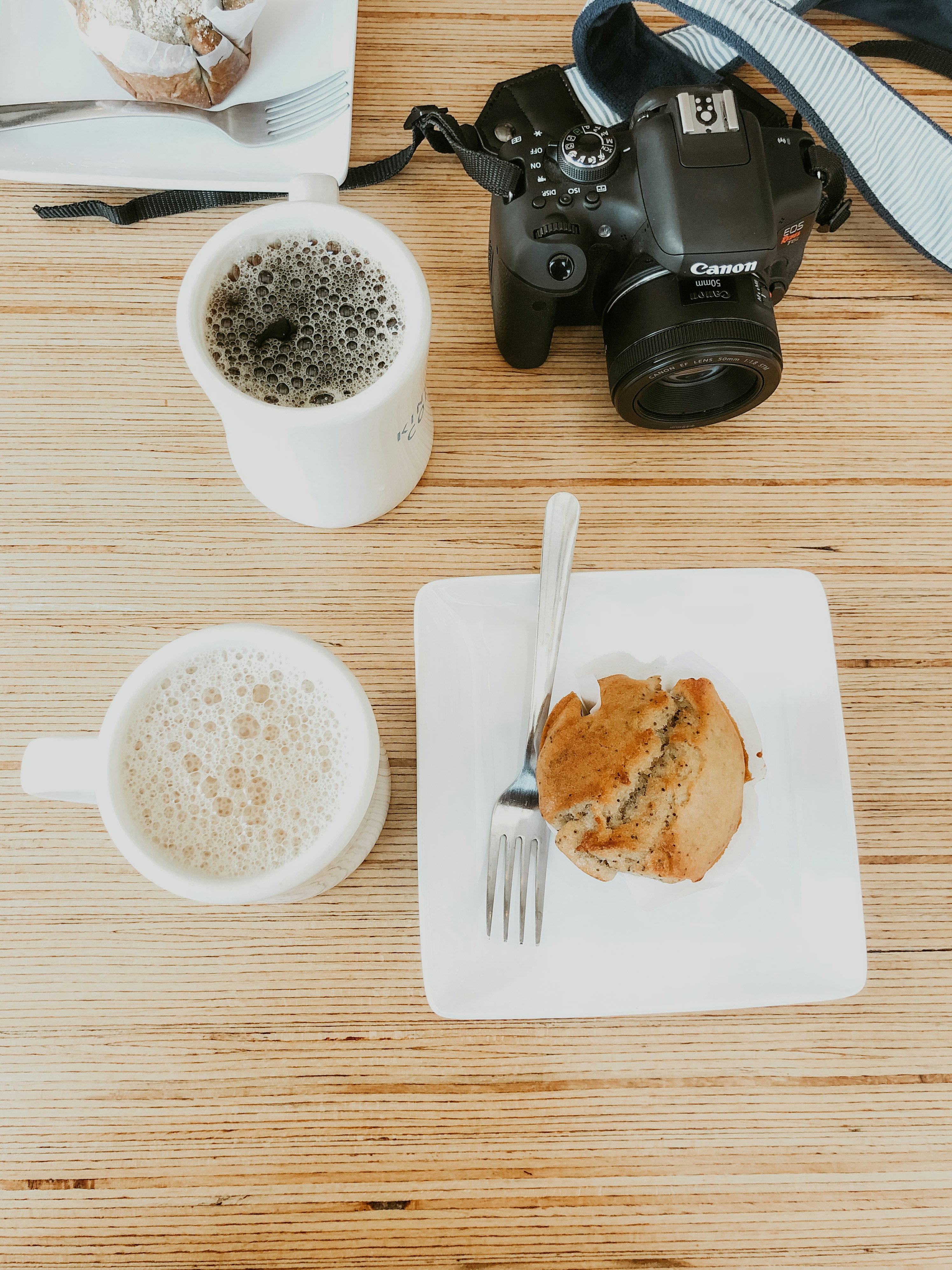 Overhead Café Moment: A Canon DSLR Among Coffee Cups and a Muffin