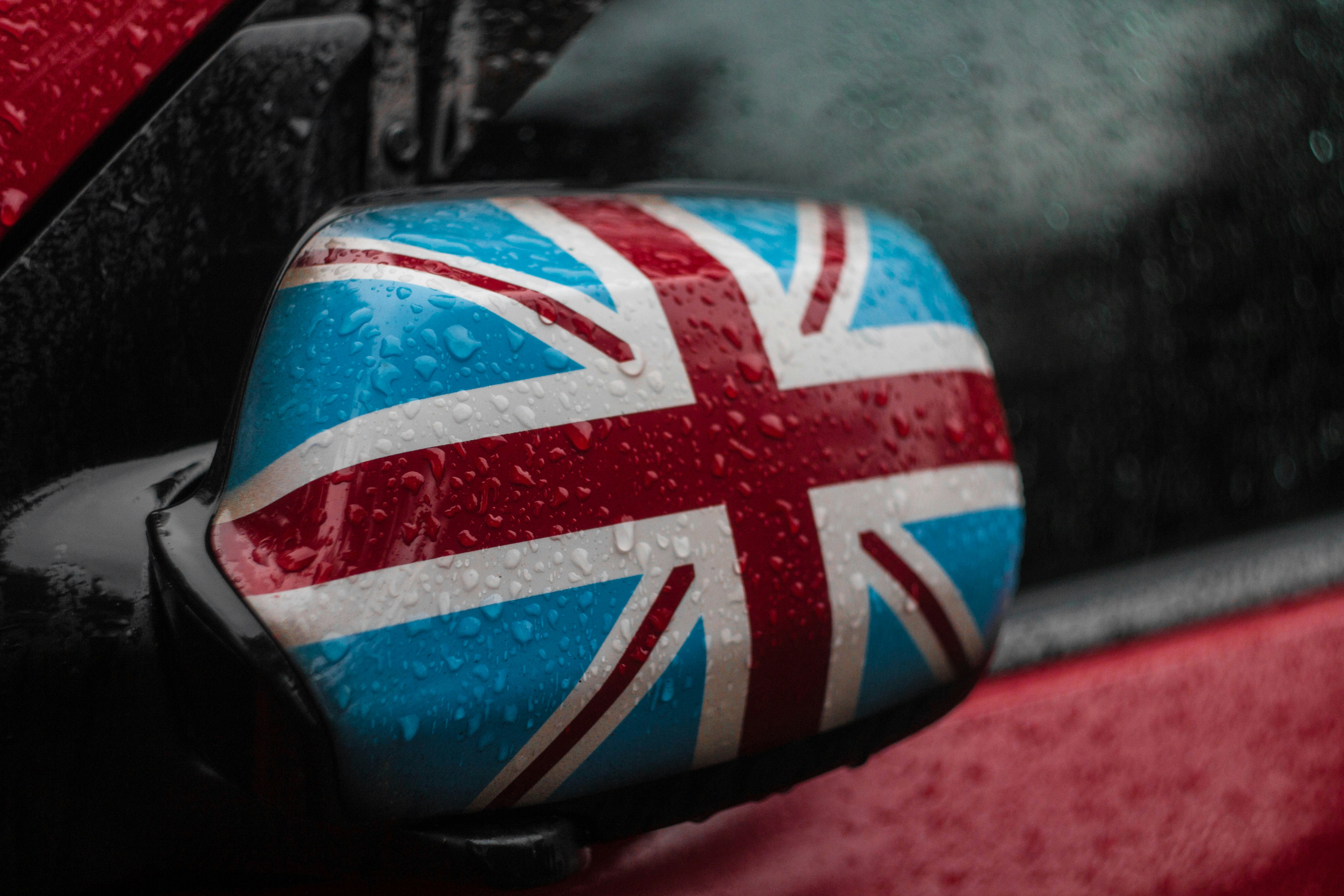 Car side mirror with a Union Jack design, covered in raindrops.