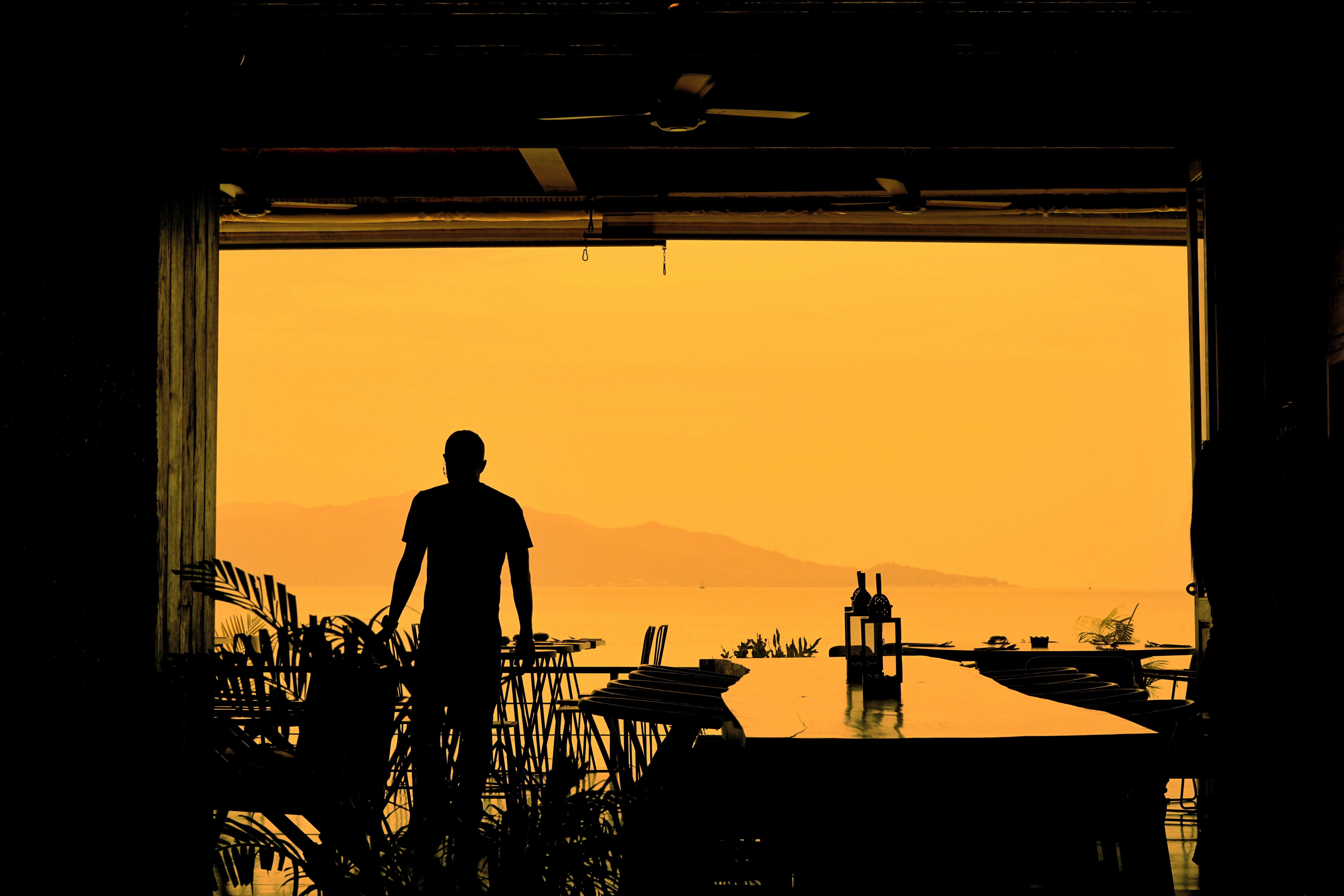 Threshold of Light: Silhouette at a Golden Harbor Doorway
