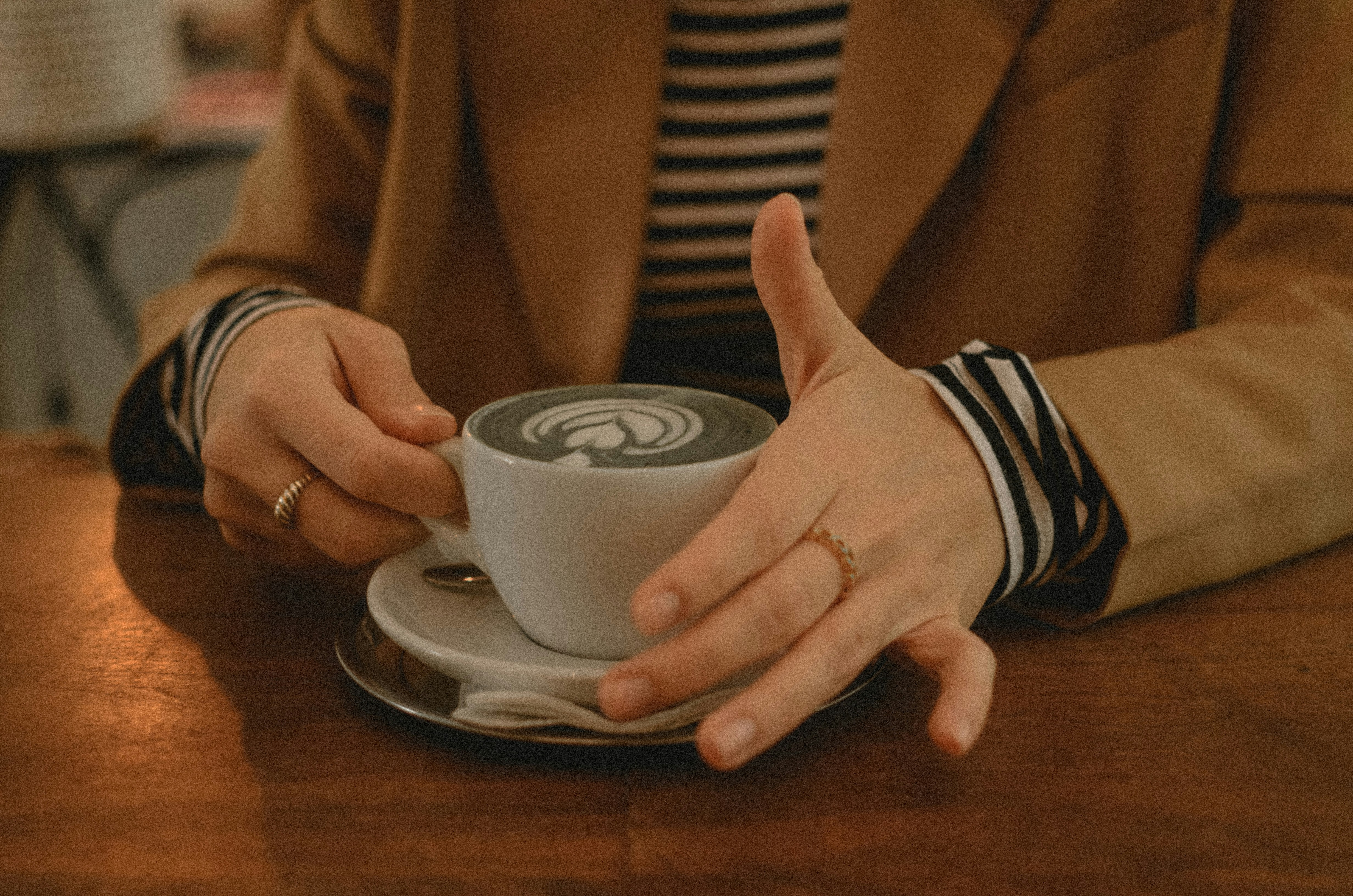 person holding white ceramic cup with saucer