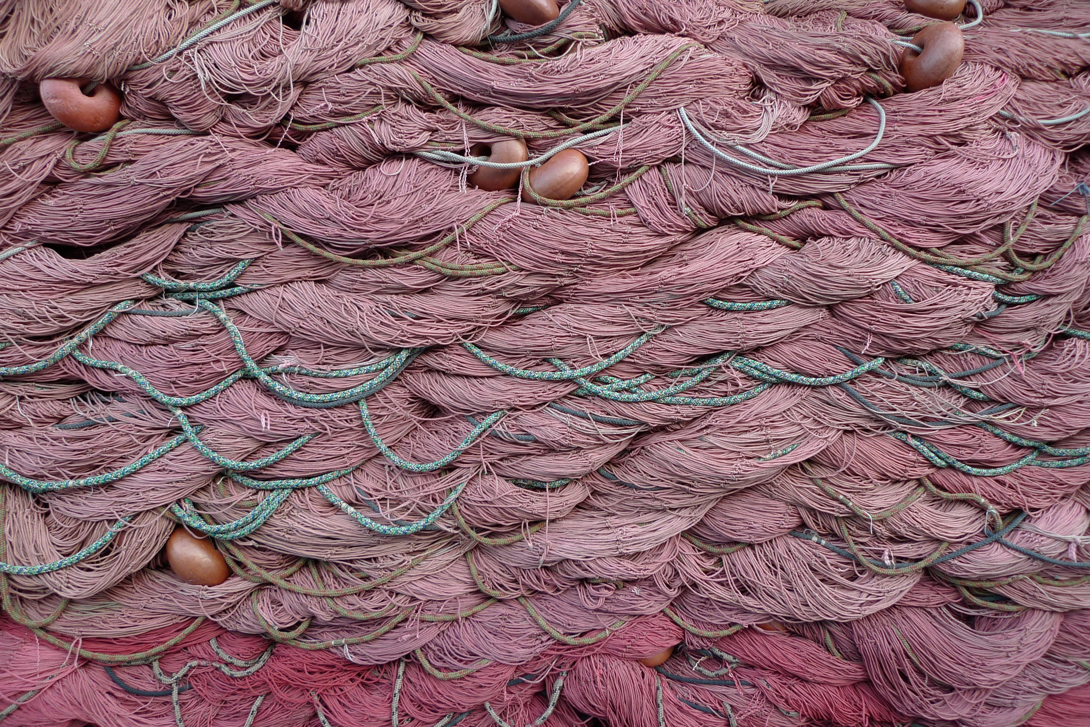 Tangled fishing nets in shades of pink and green with scattered floats.