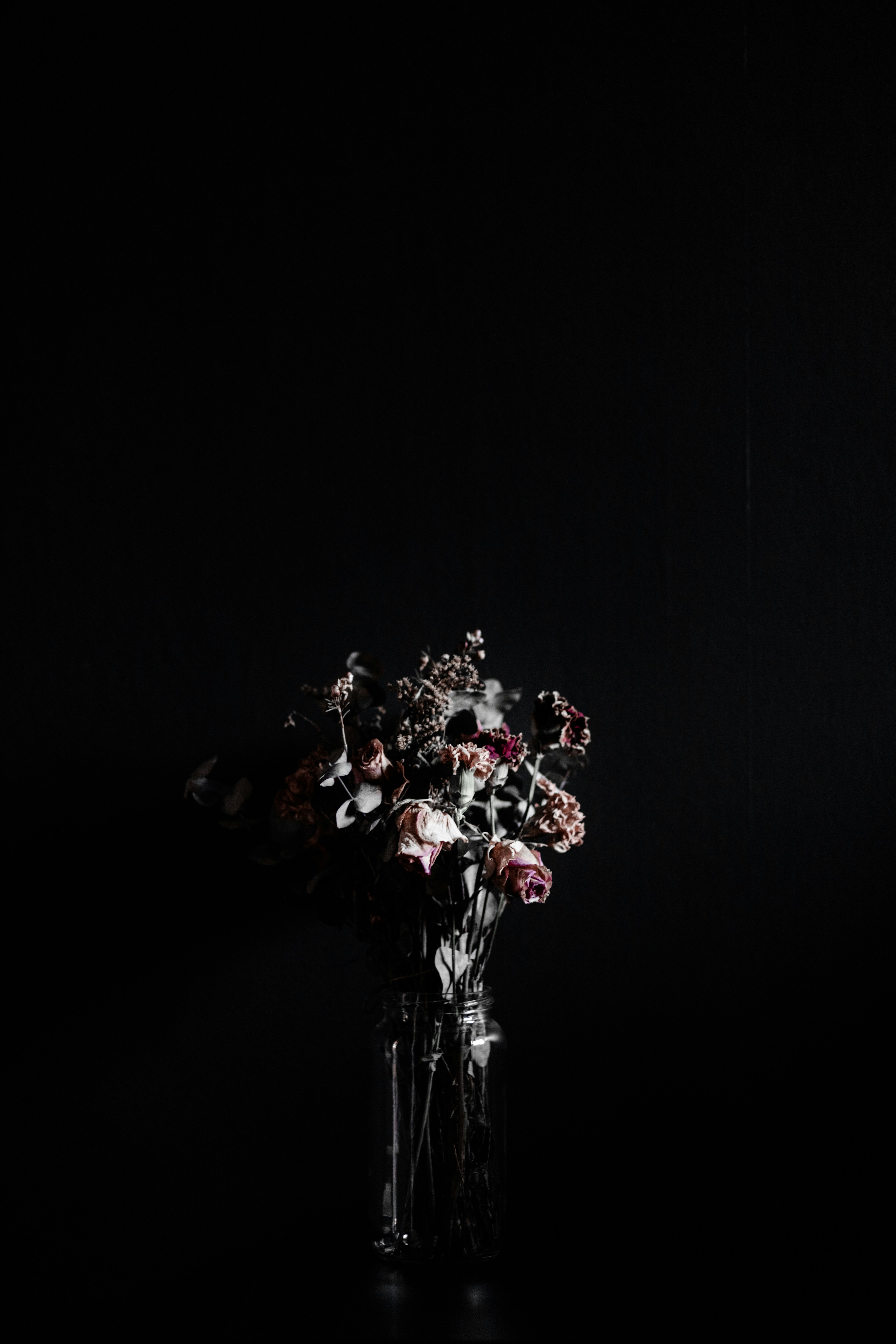 Lonely Bouquet: a Glass Vessel of Dried Flowers in Quiet Darkness