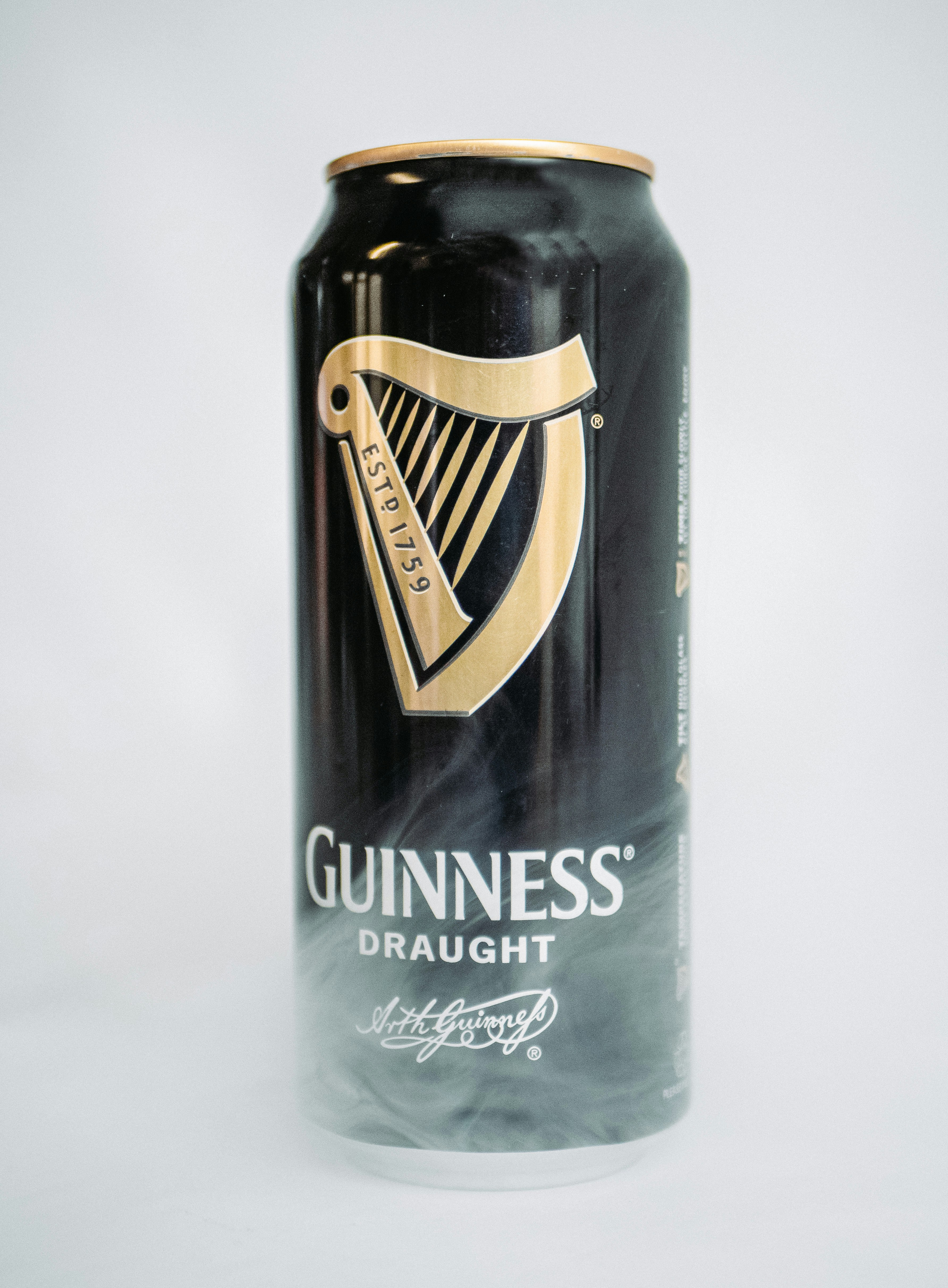 Guinness Draught can featuring the iconic harp logo against a minimalist backdrop.