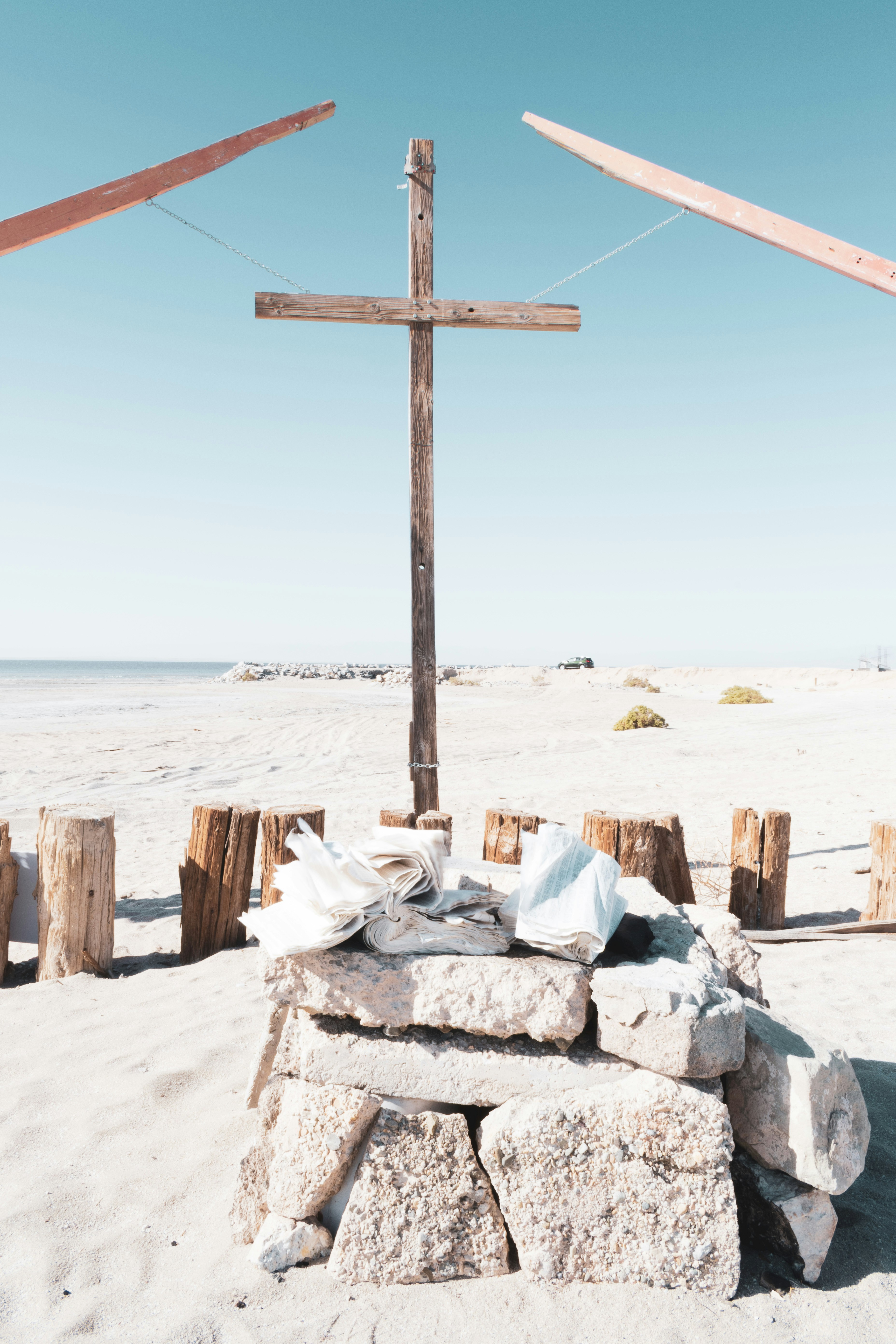 Brown wooden cross on gray rock near body of water during daytime photo ...