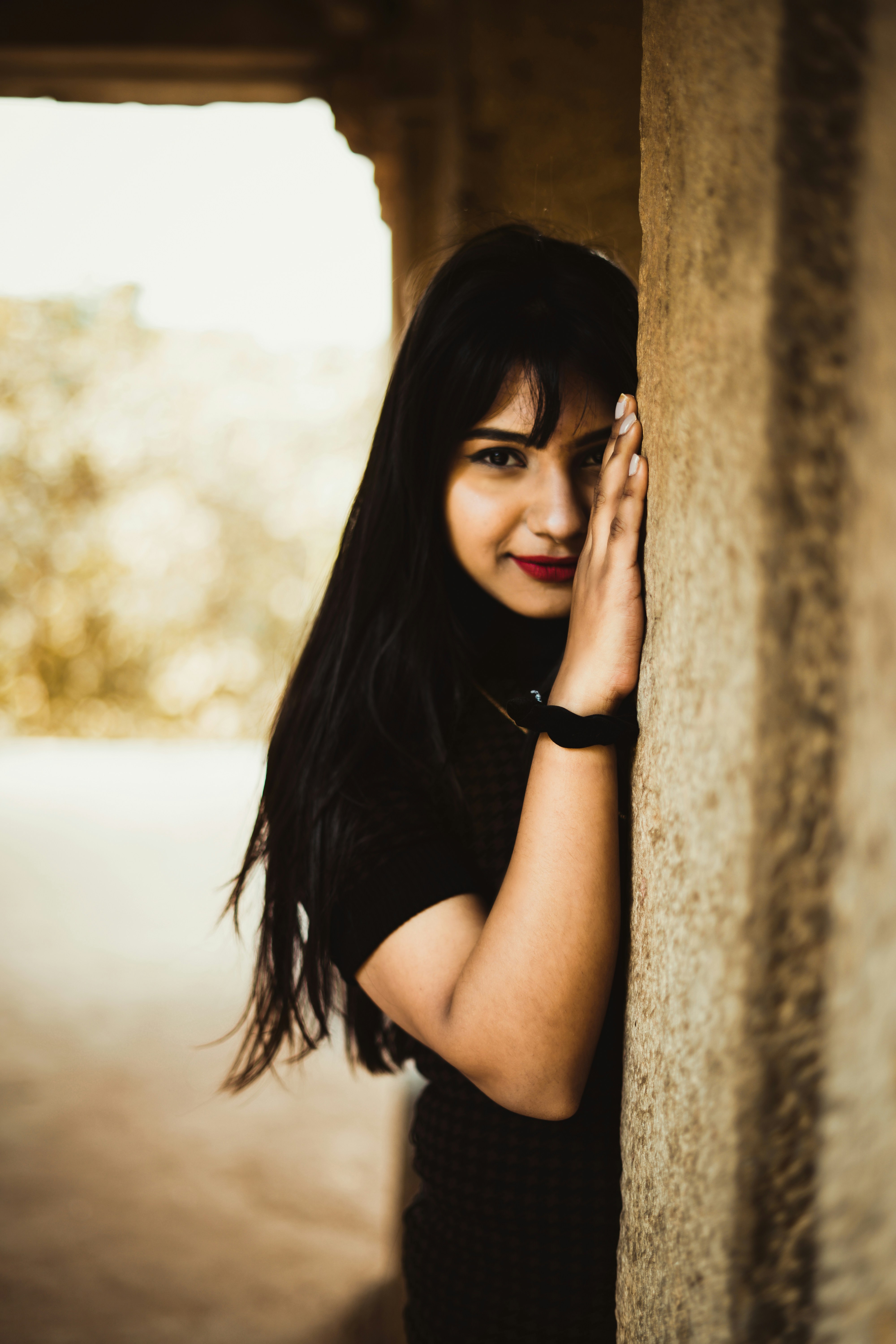 Woman in black tank top leaning on brown concrete wall during daytime ...