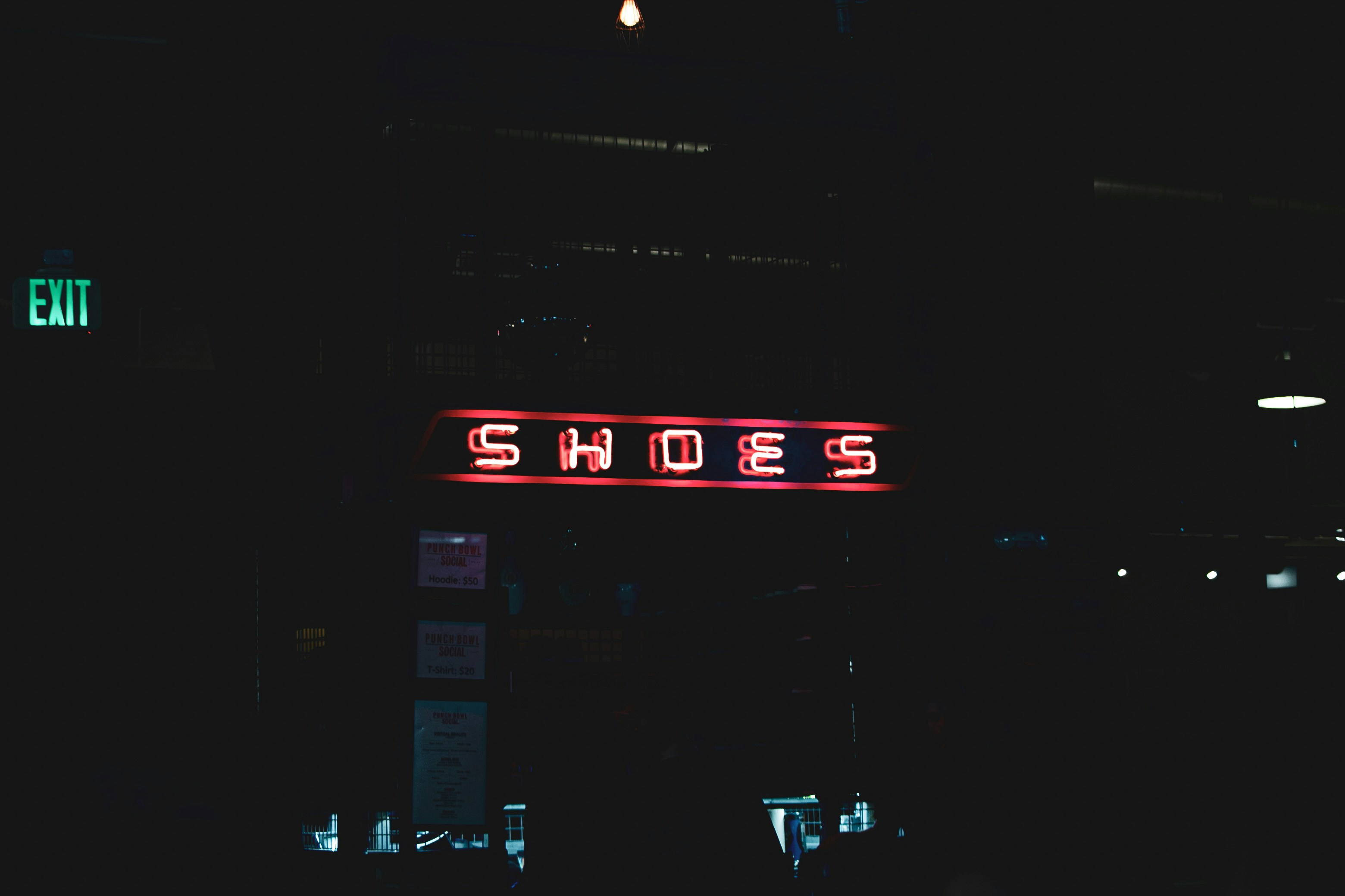 Illuminated neon sign reading 'SHOES' in a dimly lit environment, highlighting a retail space's focus on footwear.