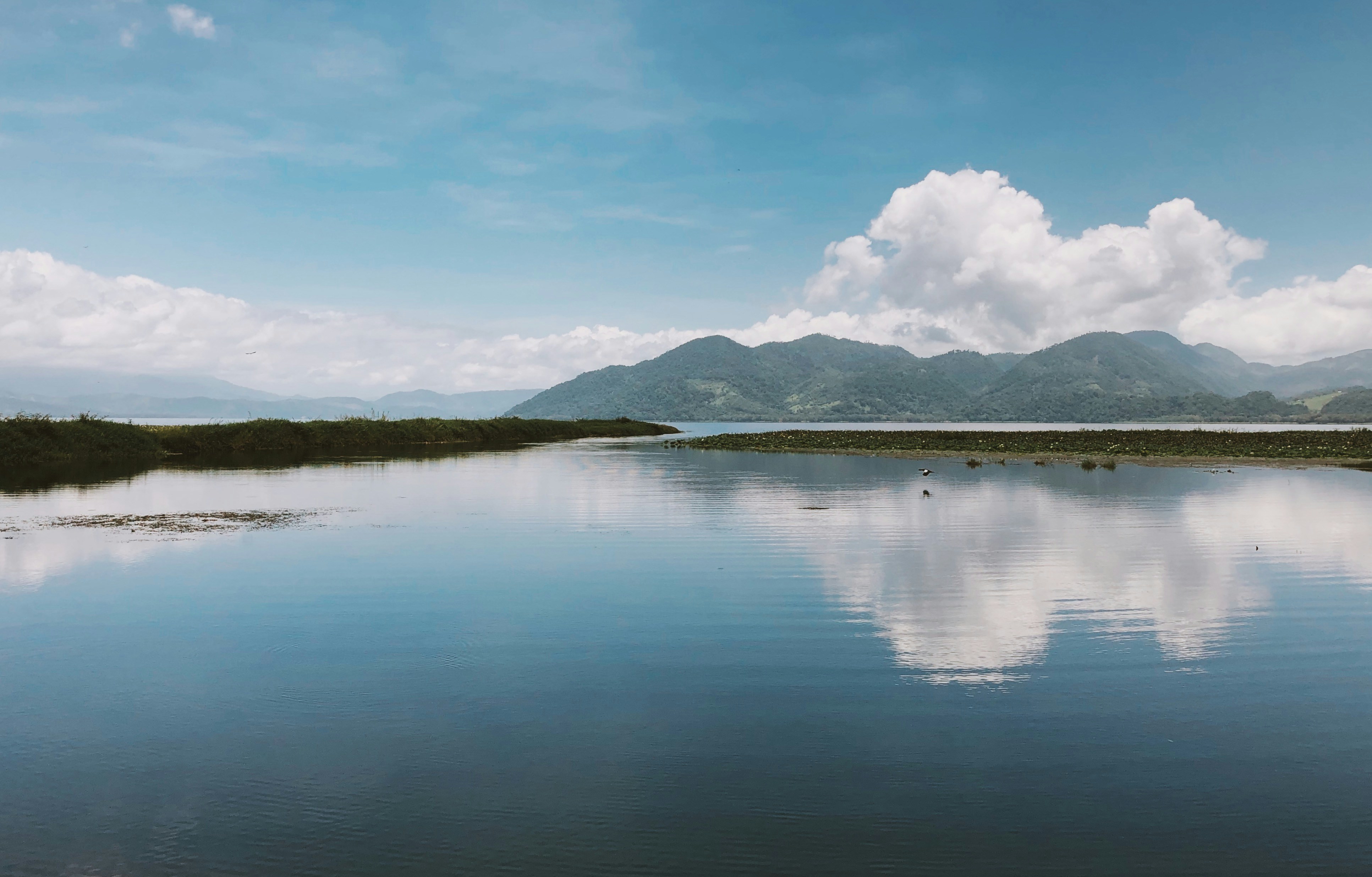 Lake near green trees and mountain under blue sky and white clouds ...