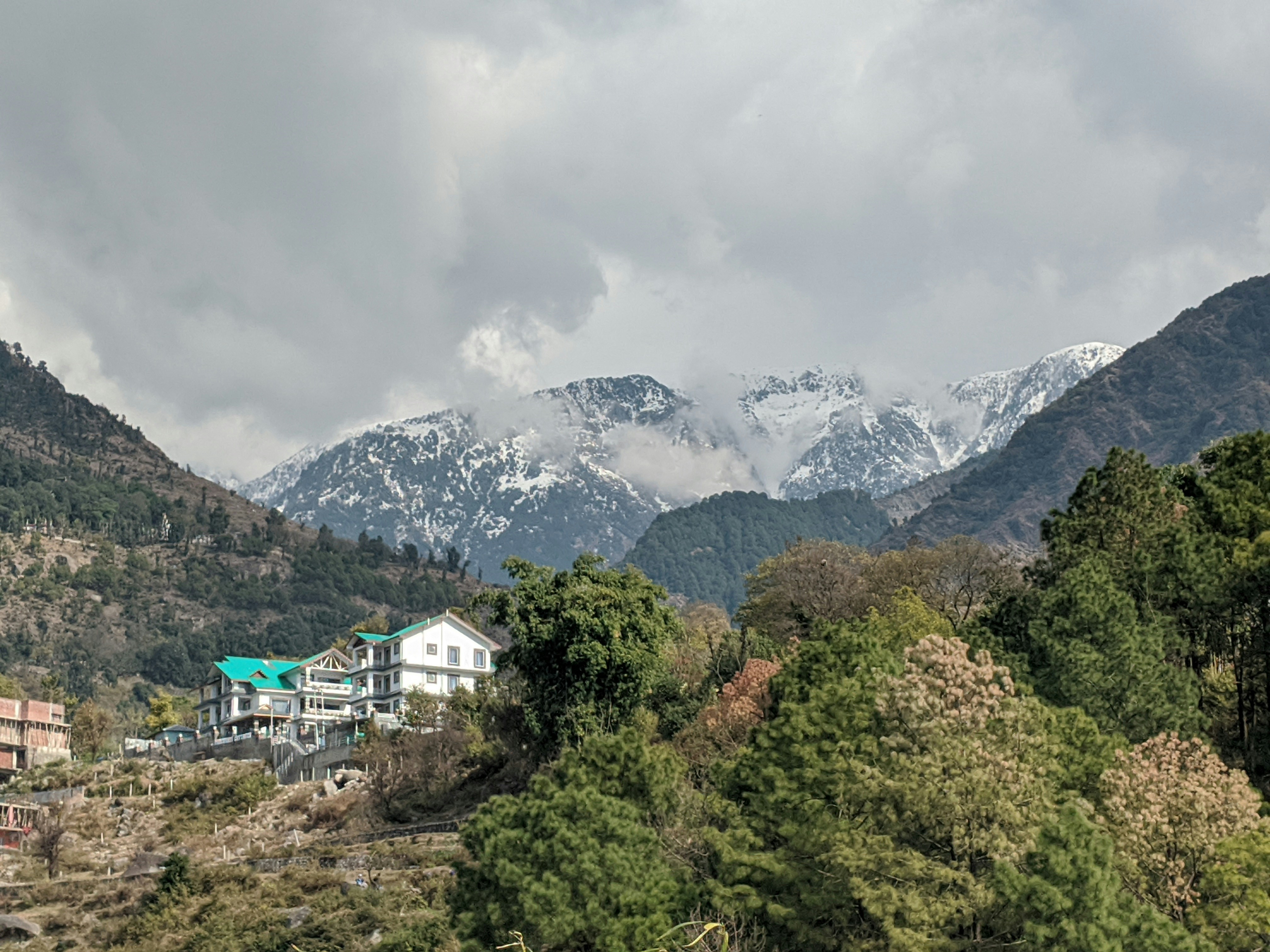 Green-roofed hillside village under a snow-dusted Alpine horizon