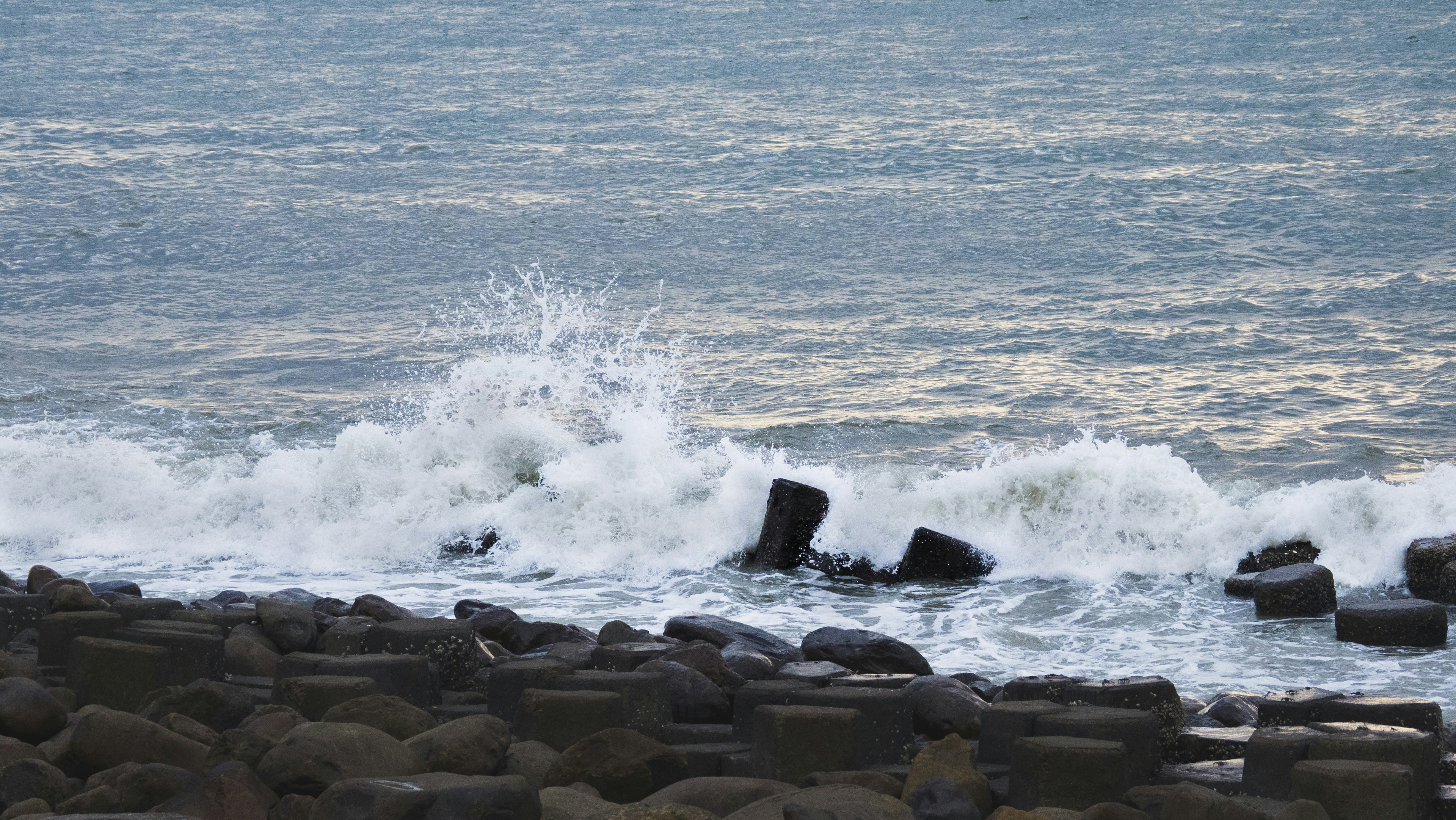 Waves crashing against rocky formations at the shoreline, capturing the dynamic interplay of water and land.