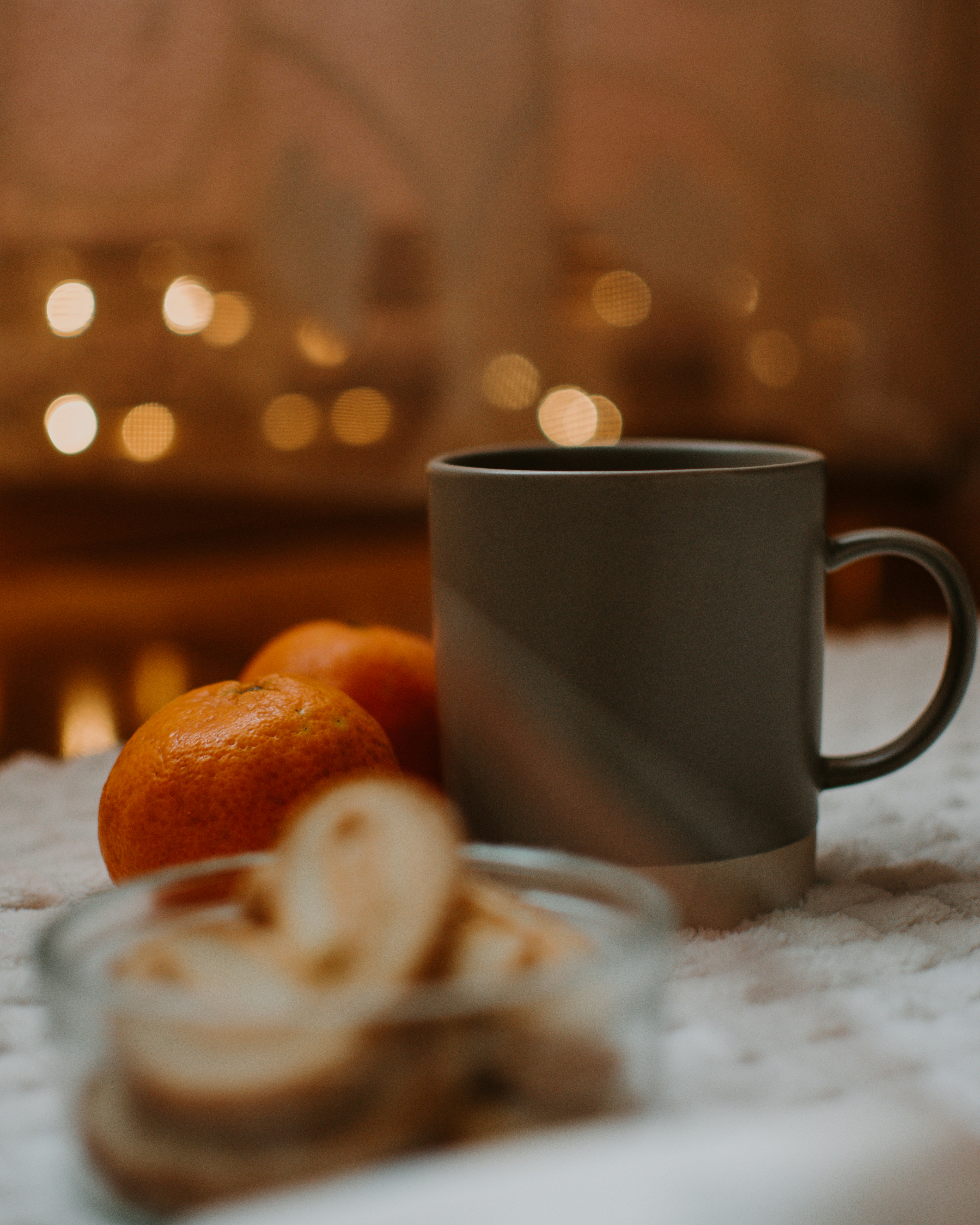 Hearthside Simplicity: A Matte Mug Surrounded by Oranges Beneath Warm Bokeh