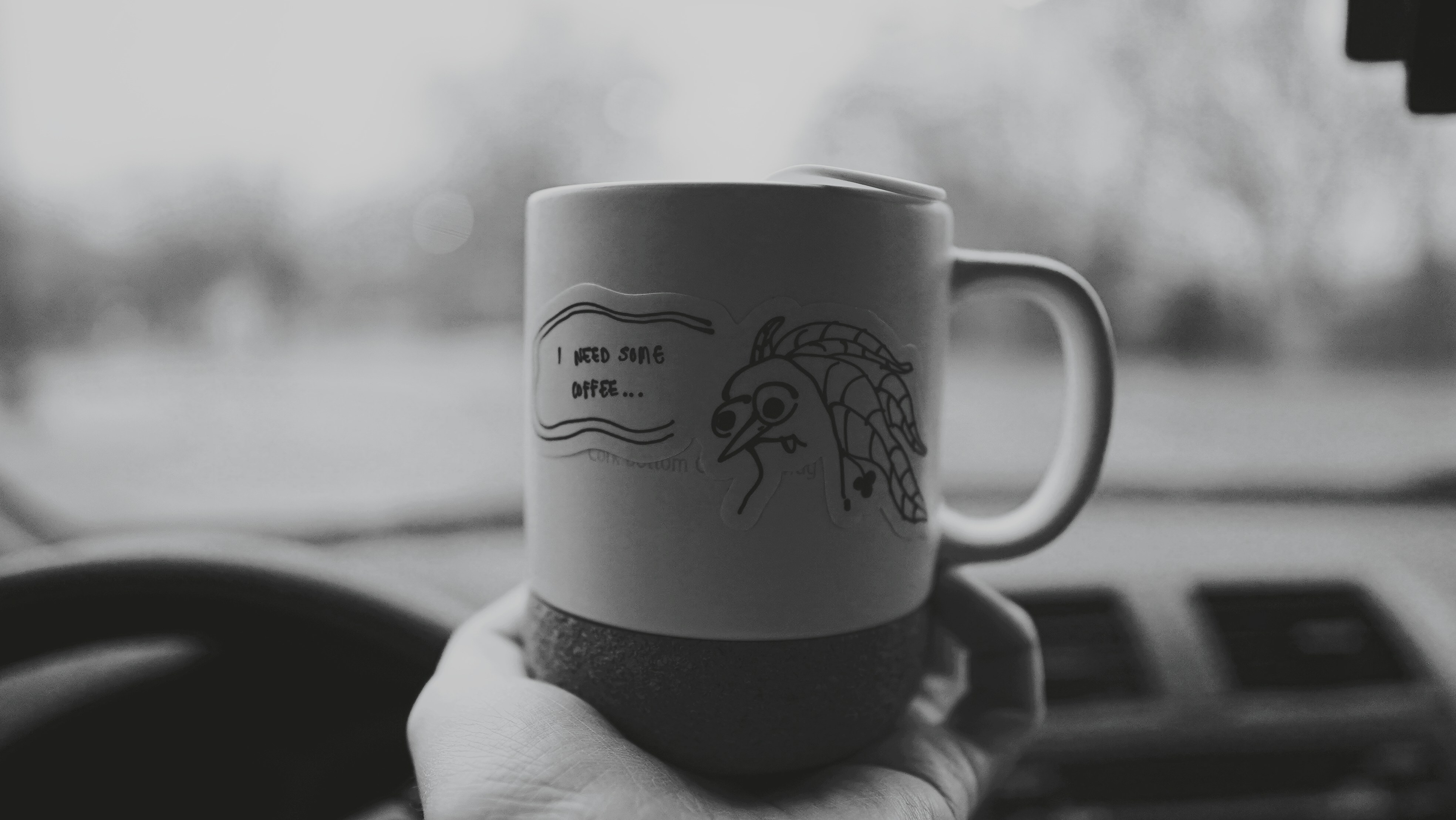 white and black ceramic mug on white textile