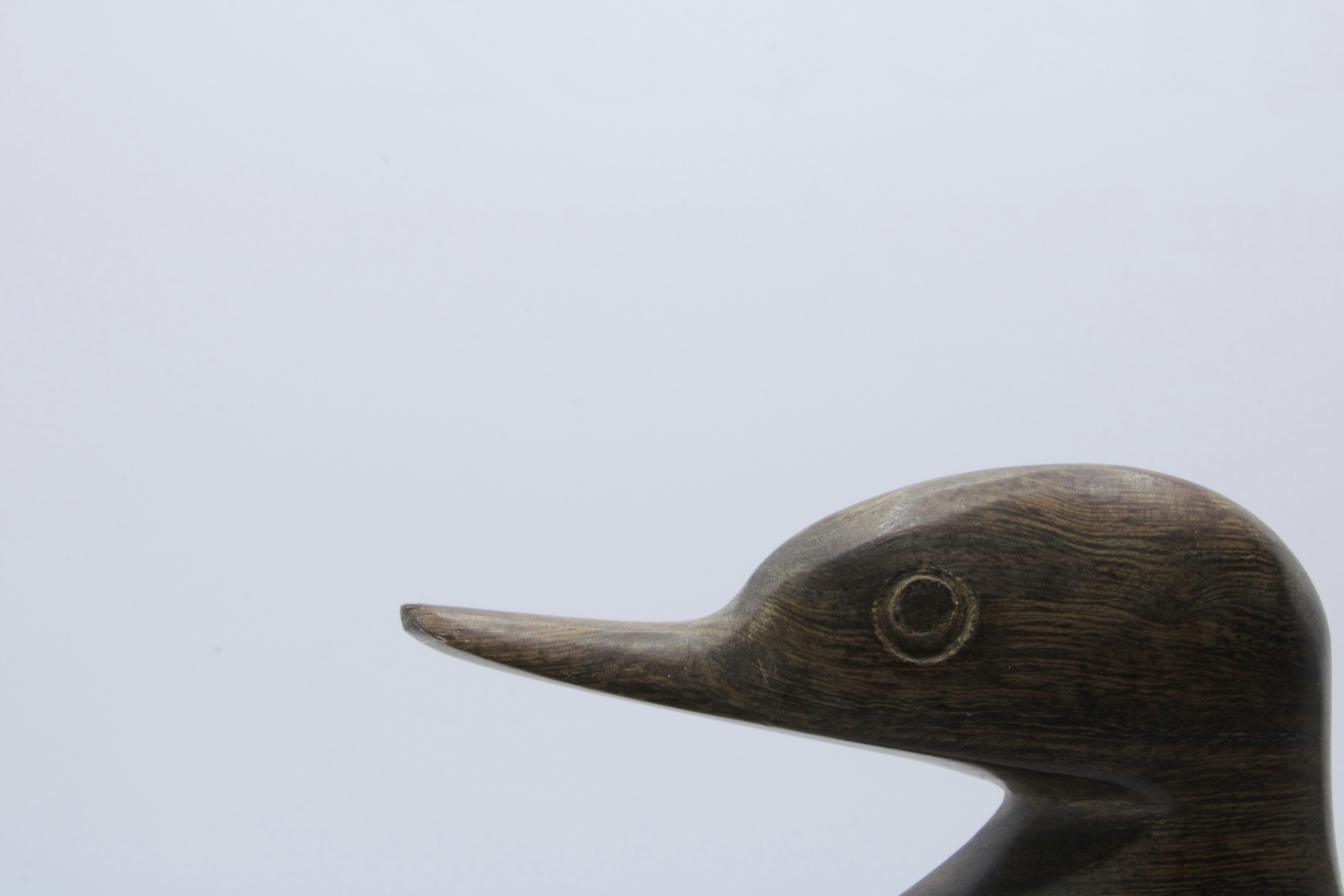 Timber Drifter: A Wooden Duck's Quiet Profile Against Pale Sky