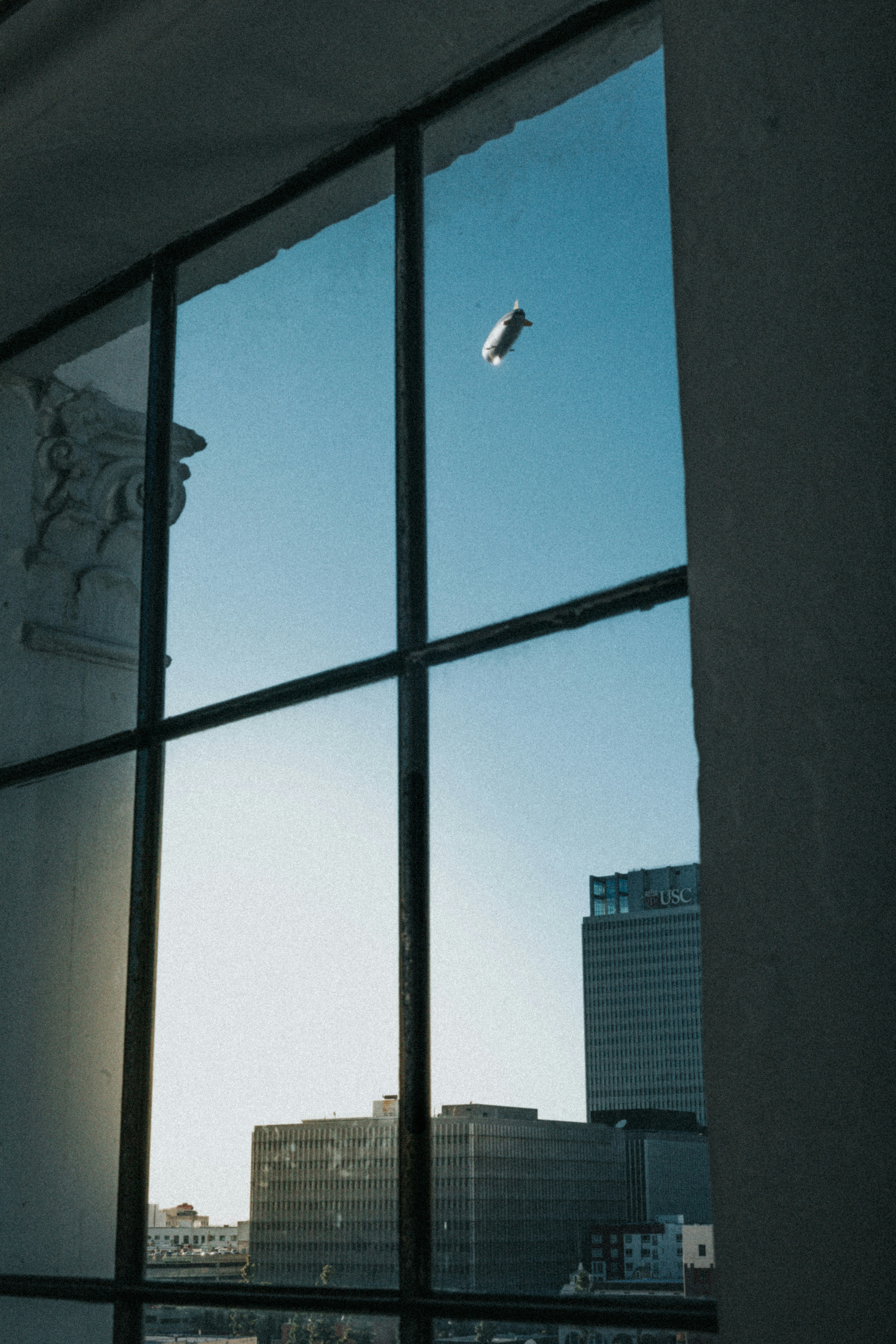 Airship Drift over a Glass-Framed Downtown: A Quiet Blue Moment