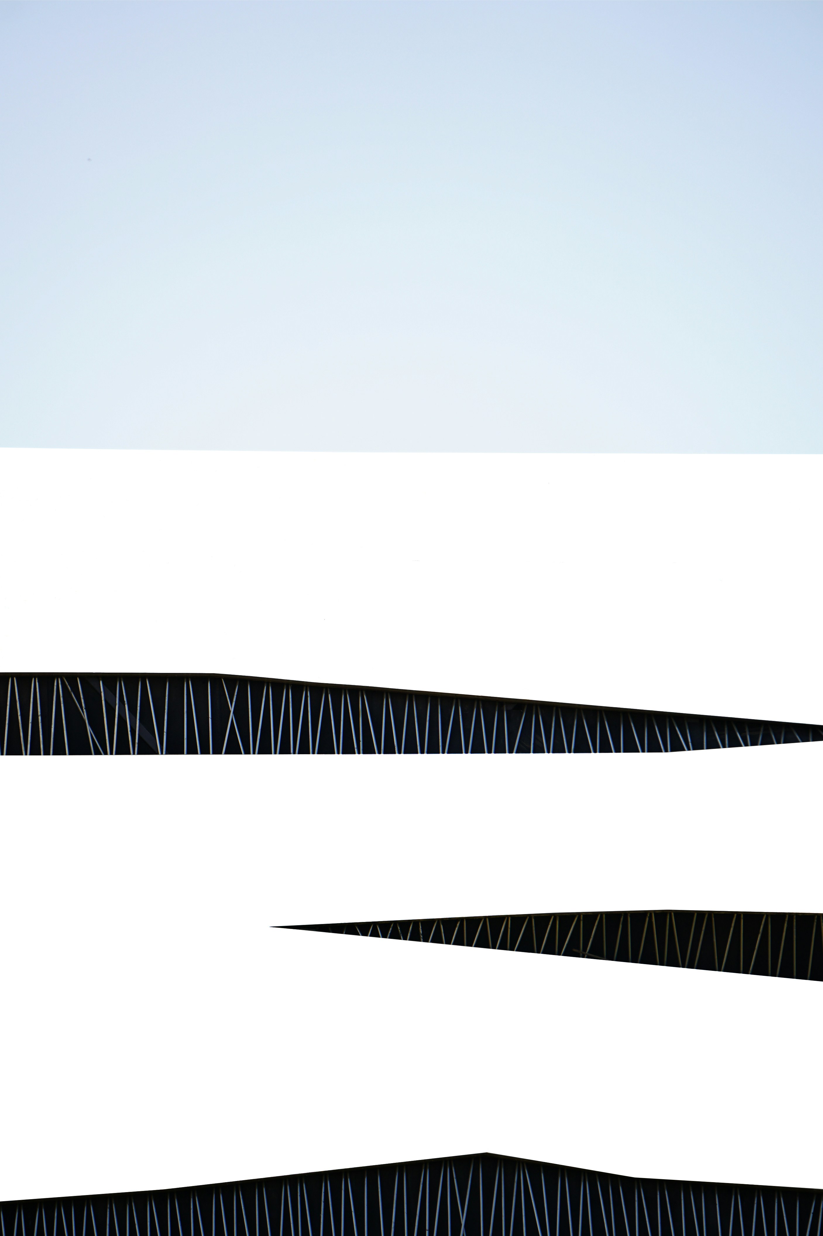 Abstract representation of angular structures contrasting against a clear sky, emphasizing geometric lines and shapes.