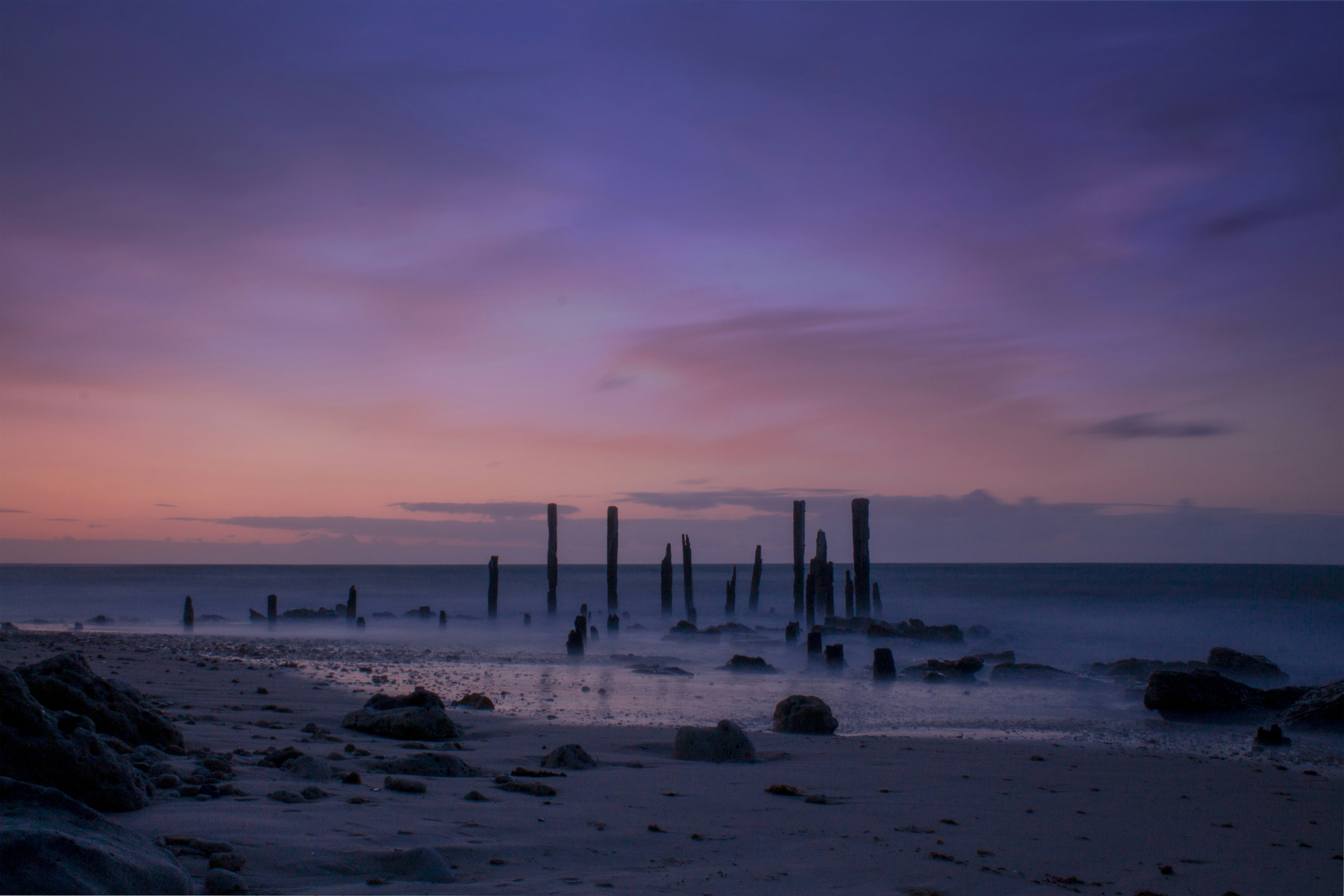 Dusk's Quiet Pier: Weathered Pilings Against Velvet Sea