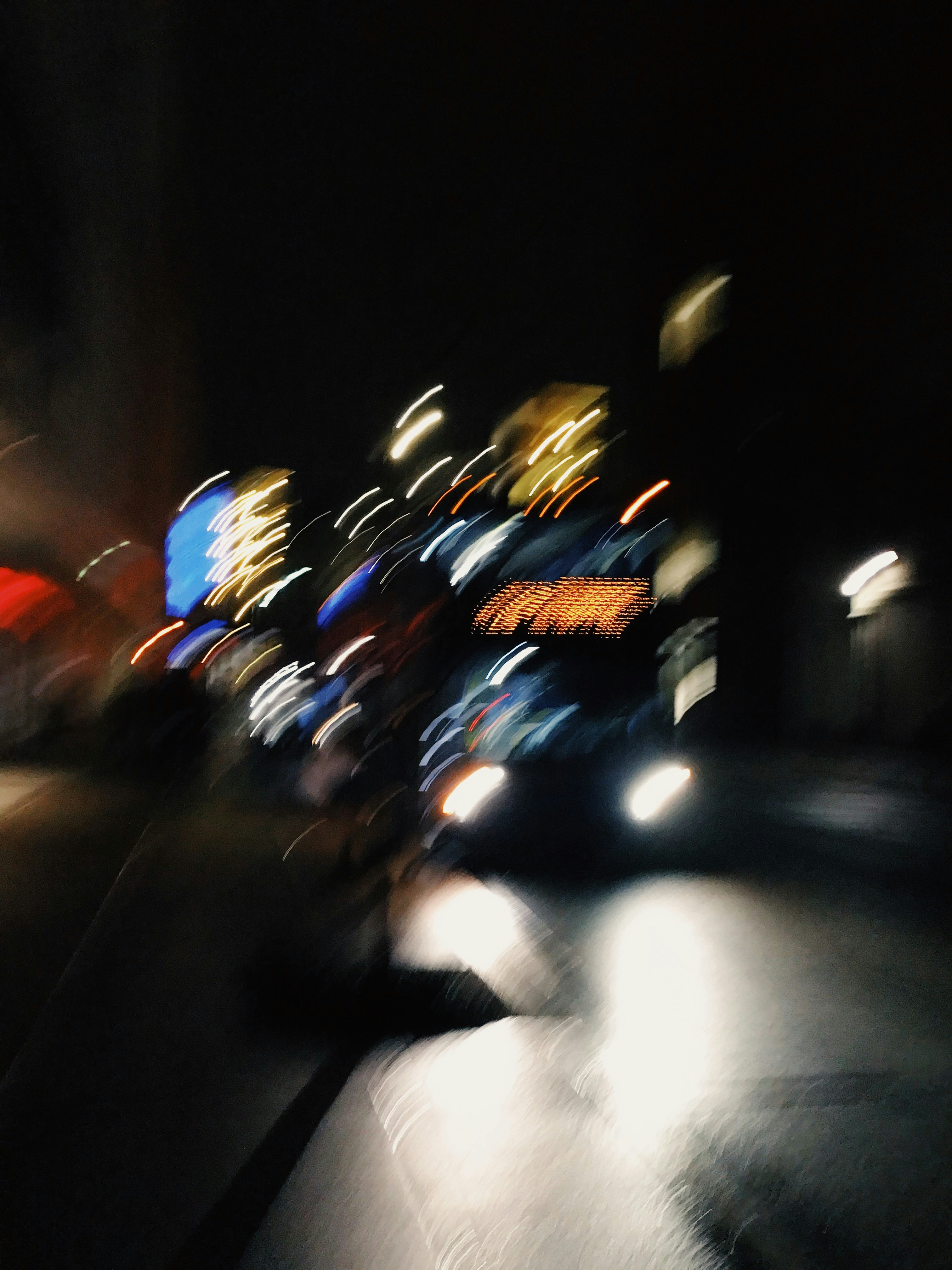 Abstract representation of city lights and movement captured at night, showcasing a blend of colors and shapes. The image emphasizes the dynamic energy of urban life.