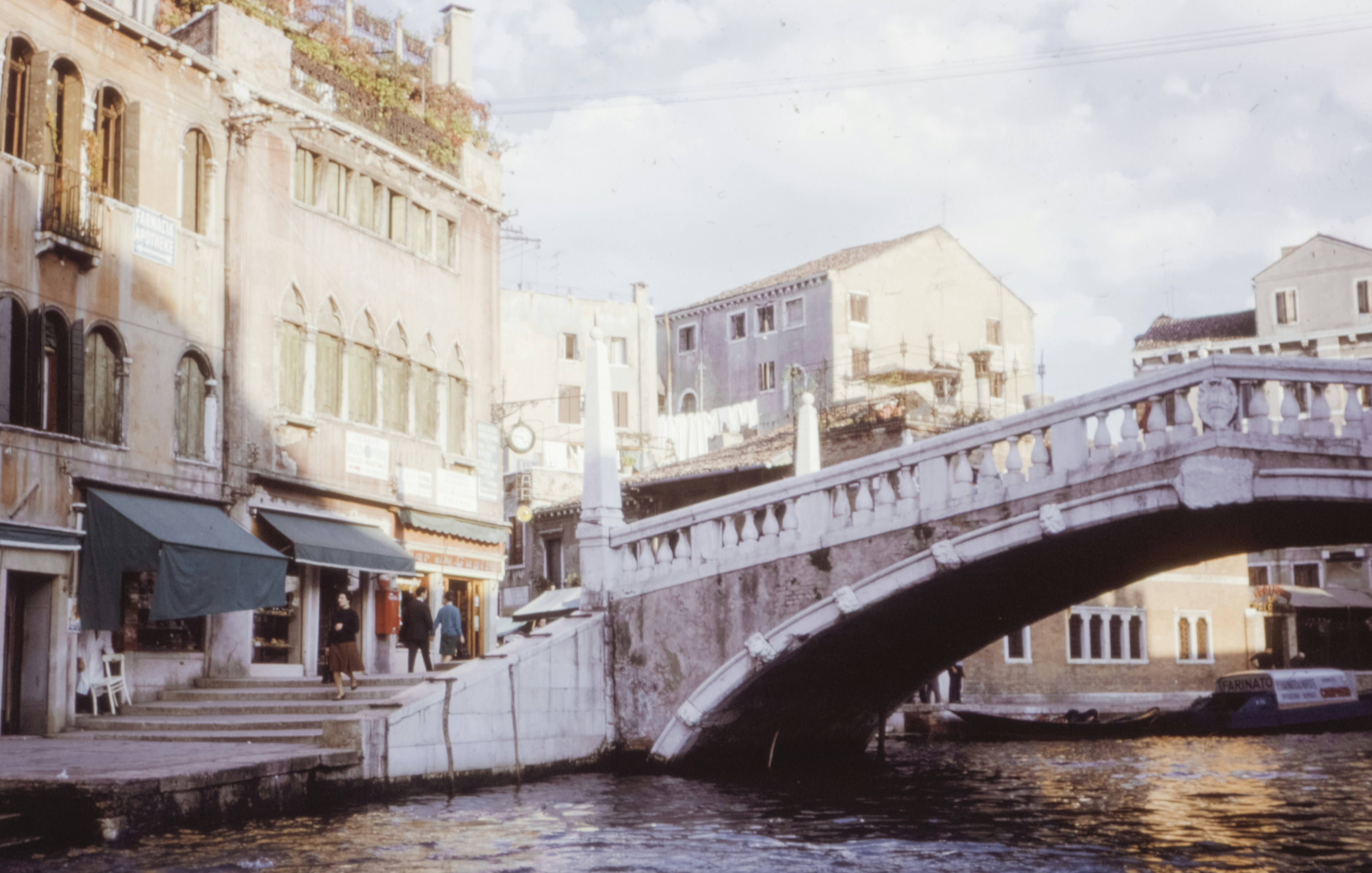 Historic arched bridge spanning a tranquil canal in Venice under a softly lit sky.