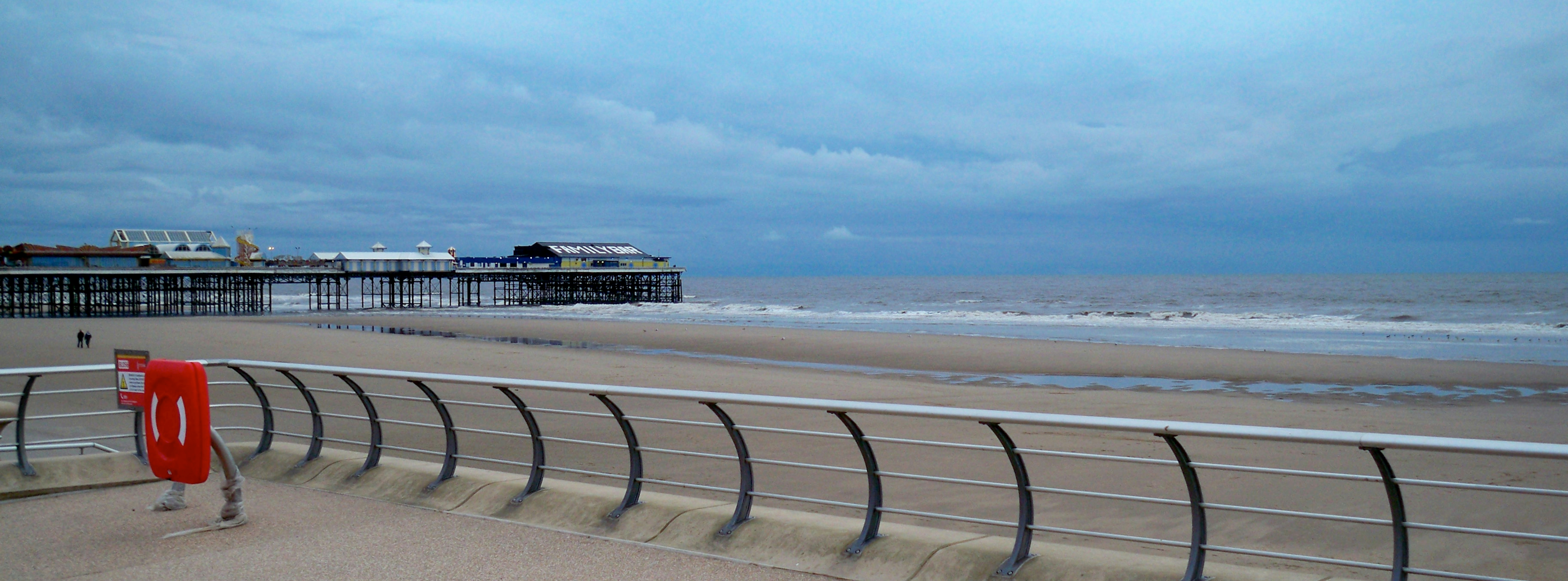 Overcast sky above the expansive sands of Blackpool's Central Pier with a red safety buoy in the foreground.
