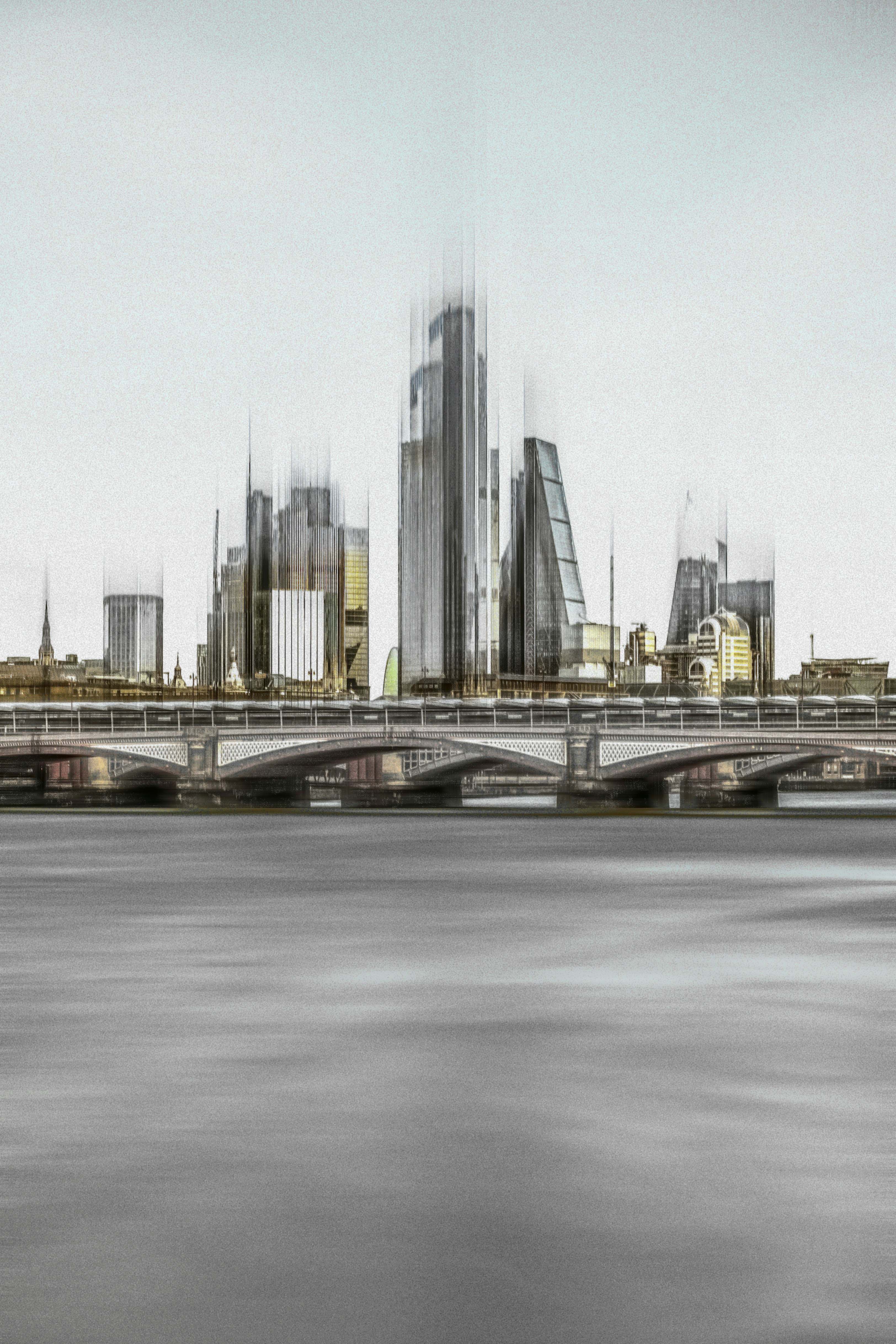 Blurred skyline of modern skyscrapers viewed from across a river, with a bridge in the foreground.