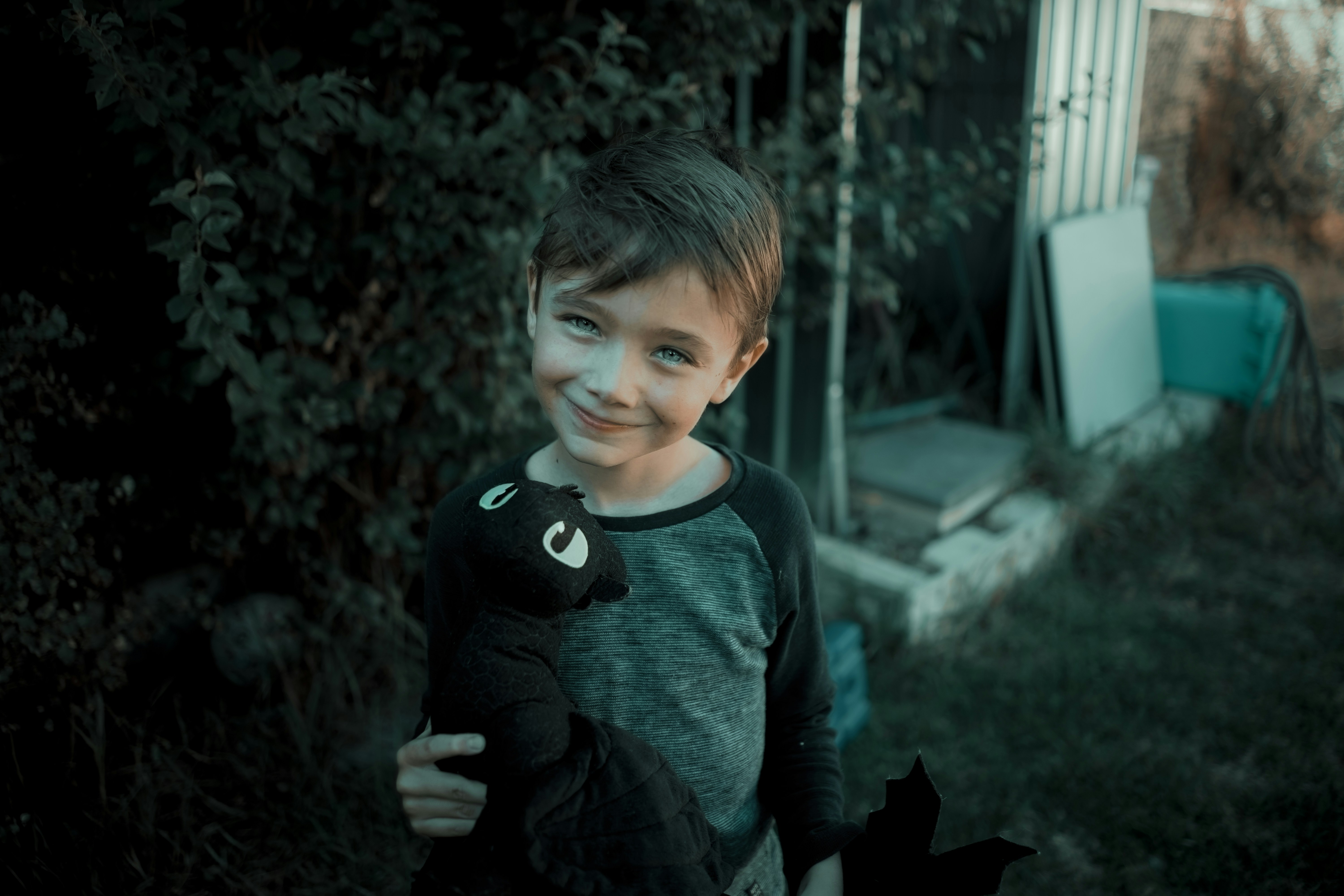 Smiling Boy with Plush Bear in a Quiet Backyard Frame