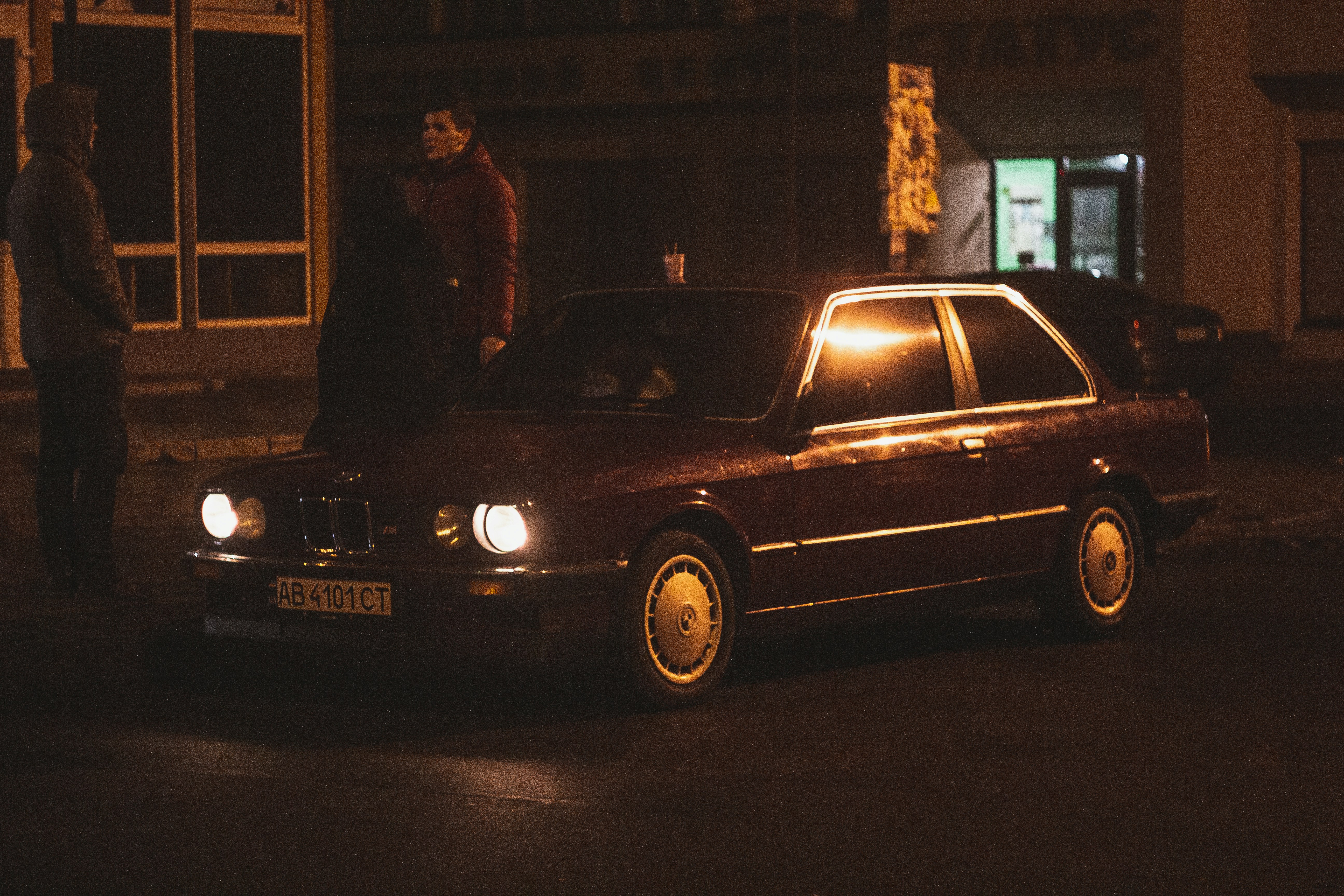 man in black coat standing beside black car