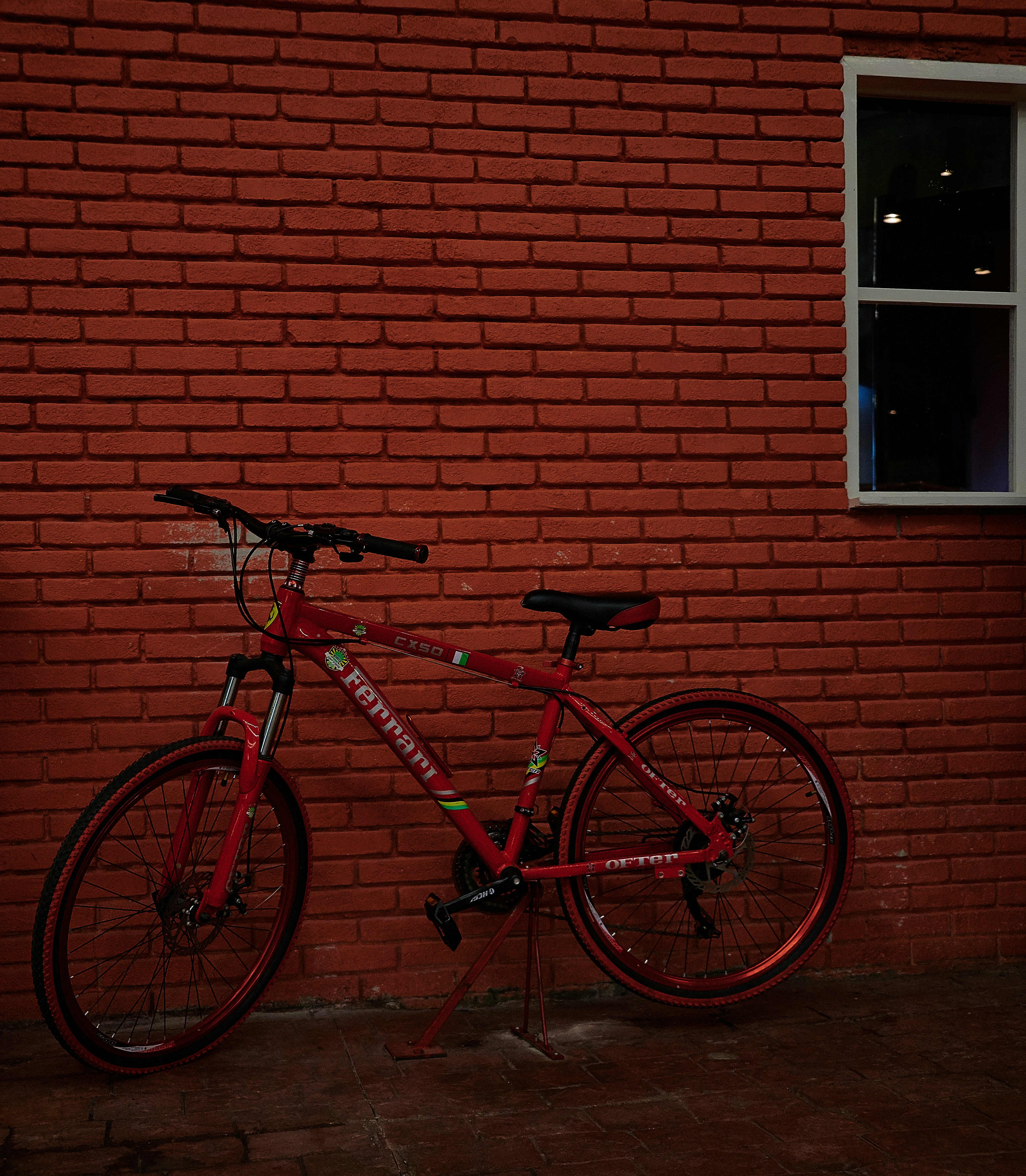 Red Steel: A City Bike Resting Against a Brick Backdrop