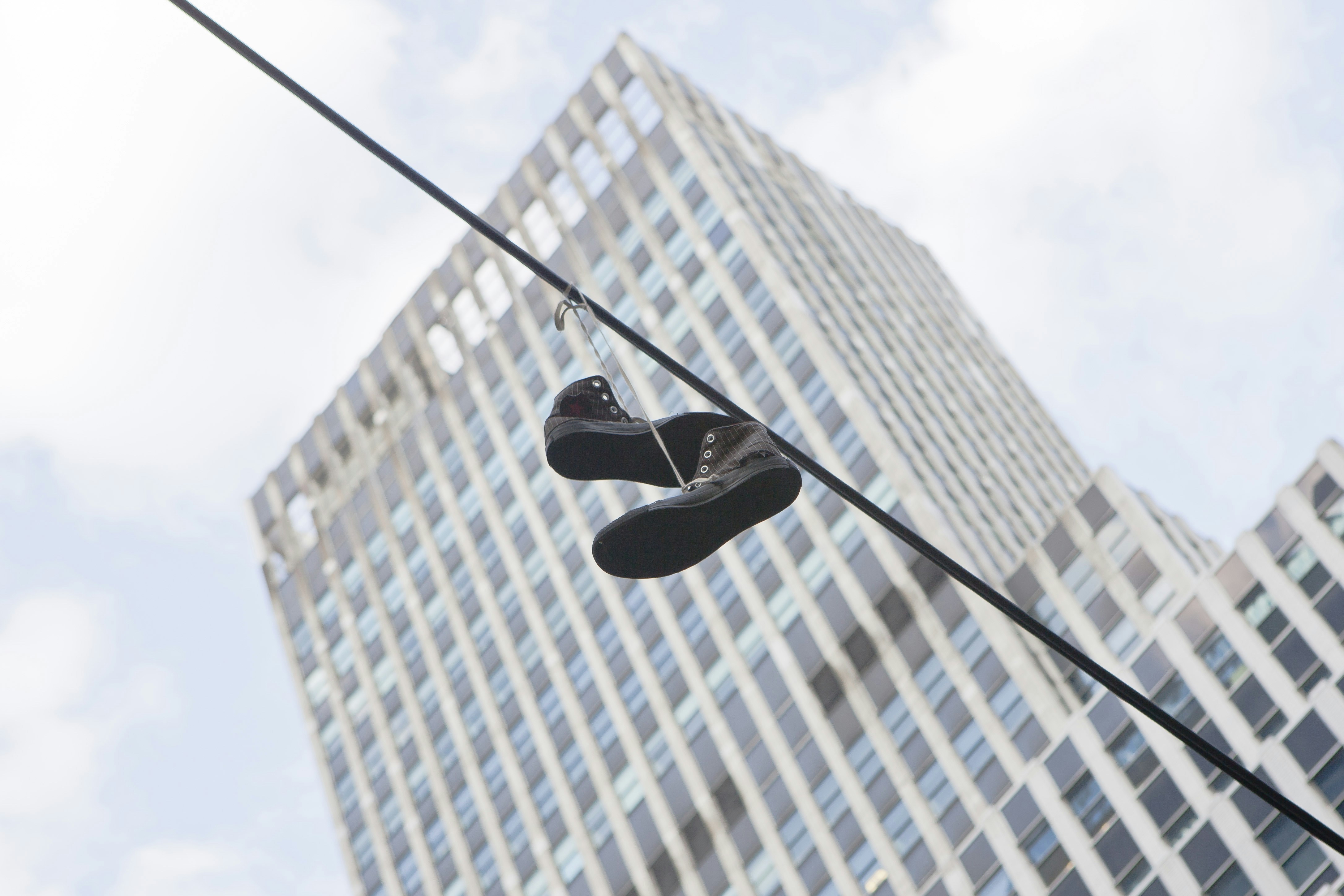 Shoes on a Cable Above the City Glass