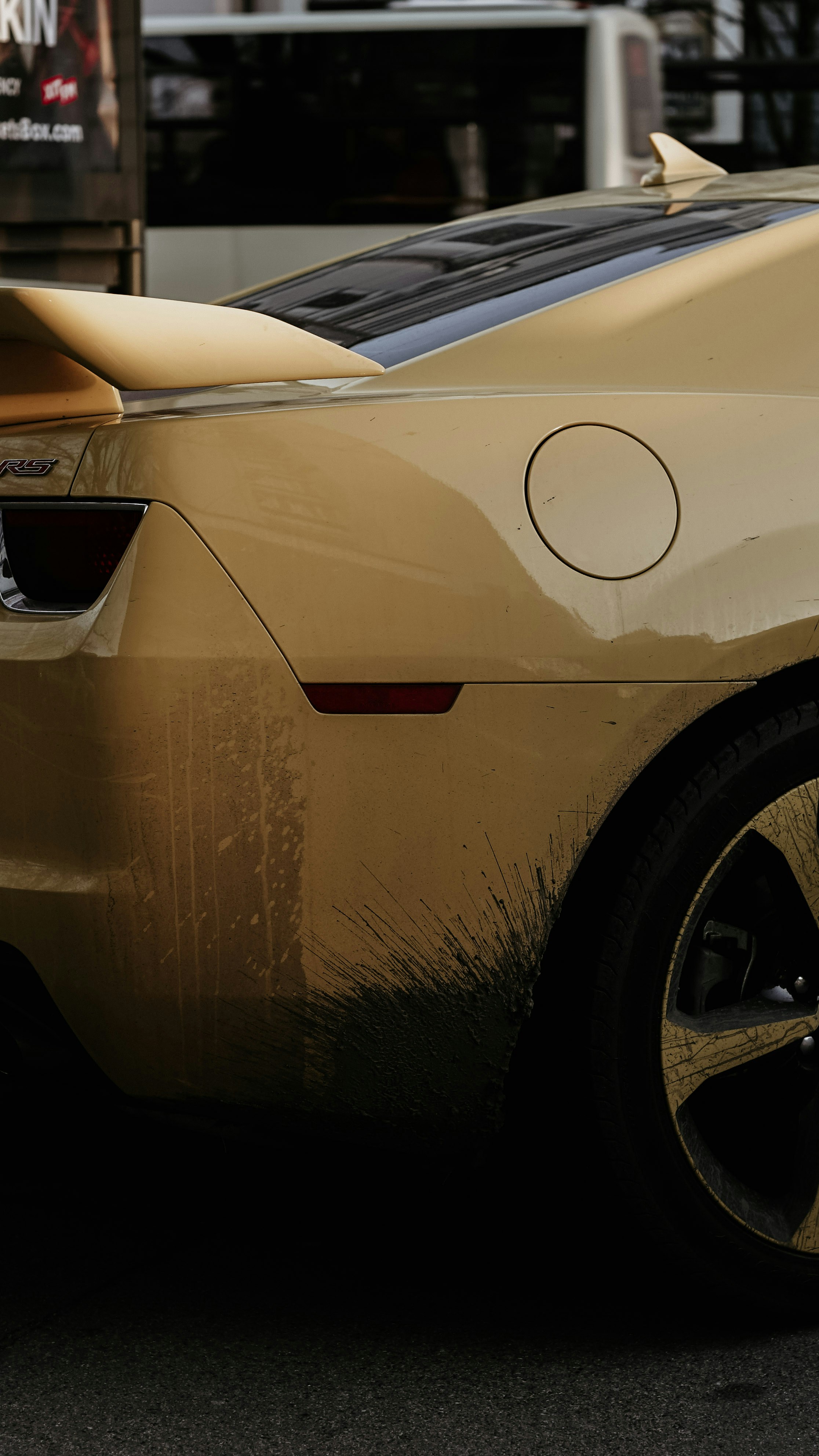 Gold Grime on a Street Racer: Mud-Splashed Rear Quarter Under City Light