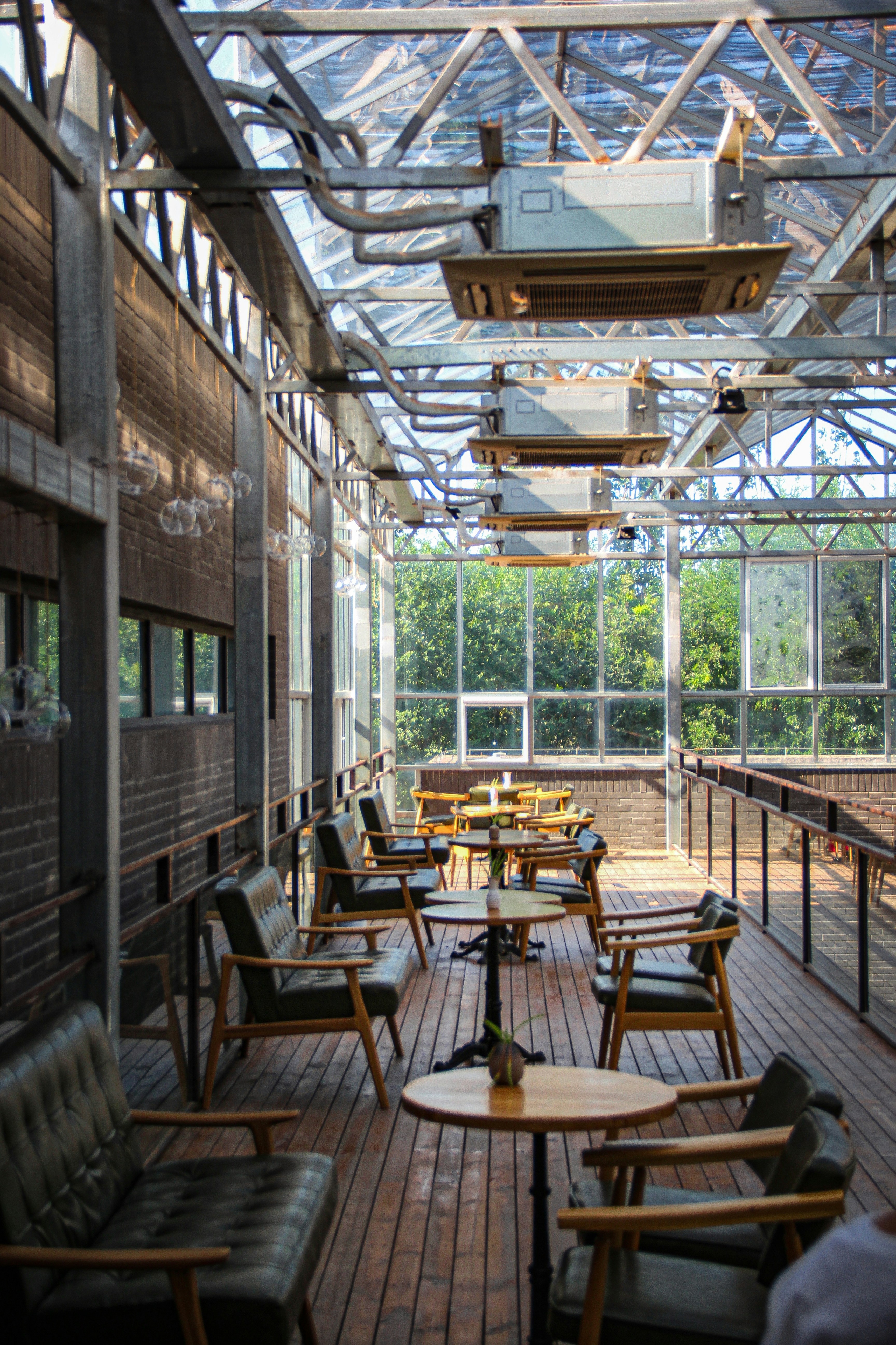 Sunlit Conservatory Café: Rows of Round Tables Beneath Industrial Glass
