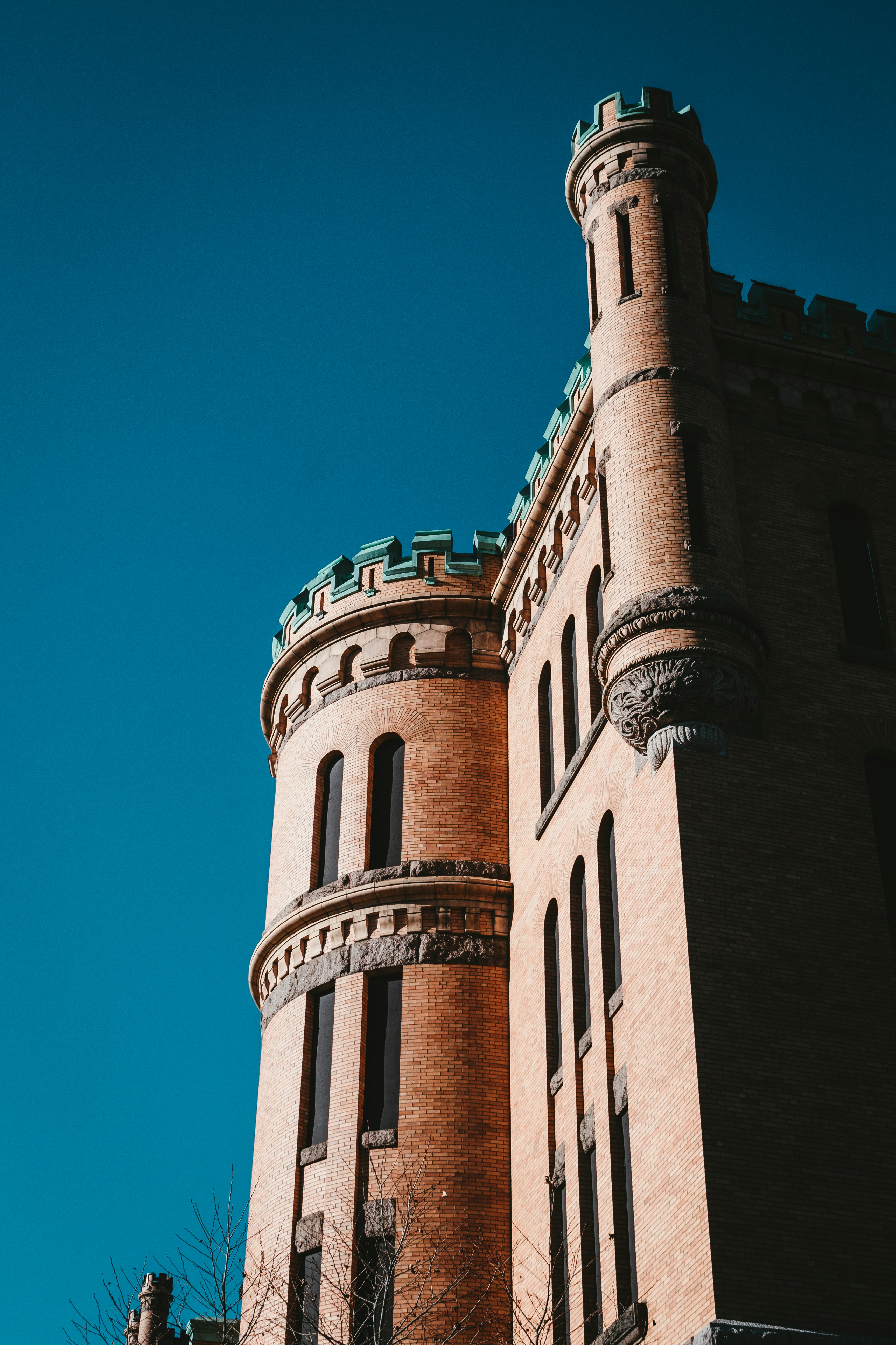 Historic brick tower with ornate detailing against a vibrant blue sky.