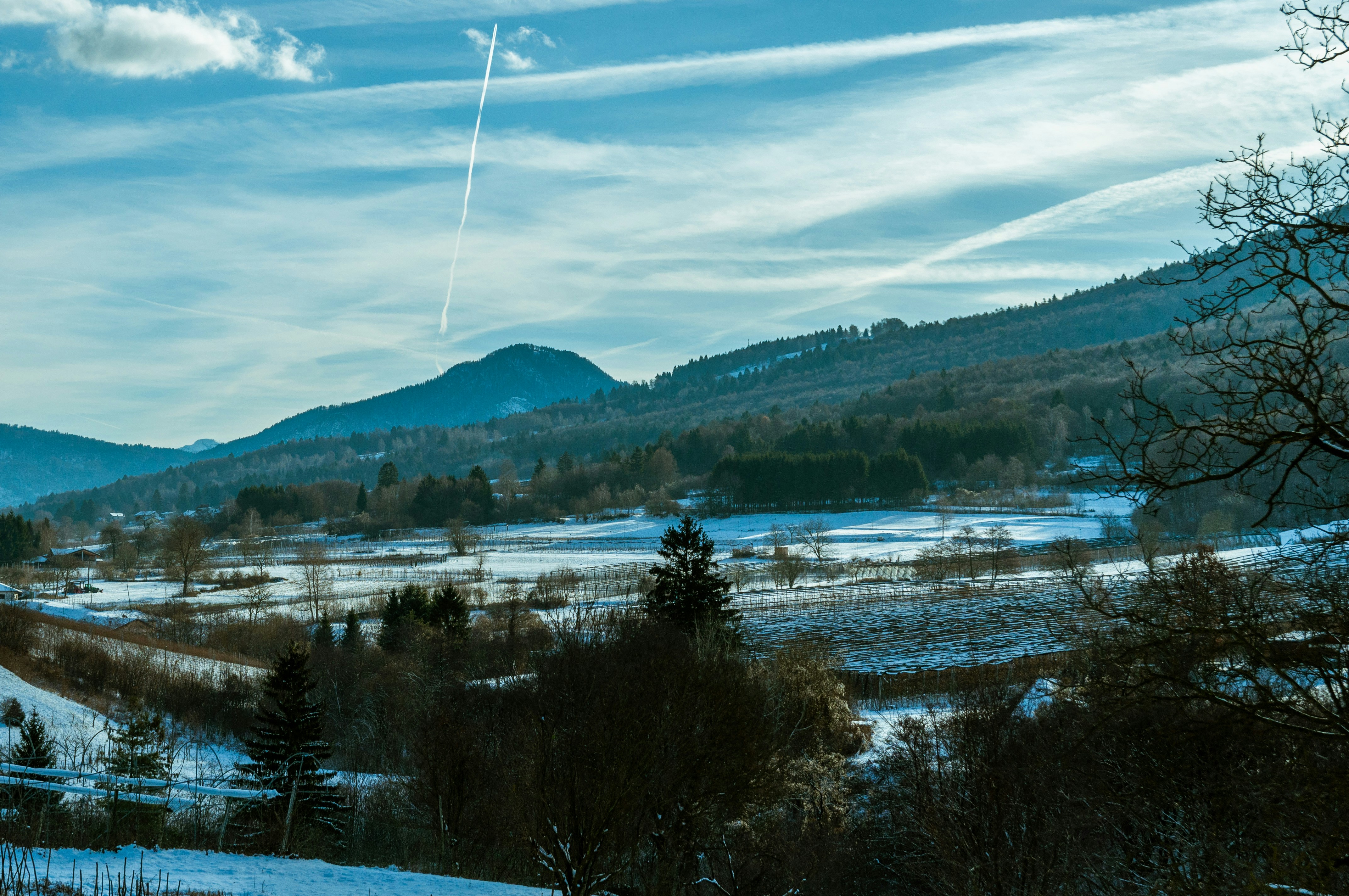 Snow-dusted landscape with rolling hills under a streaked sky.