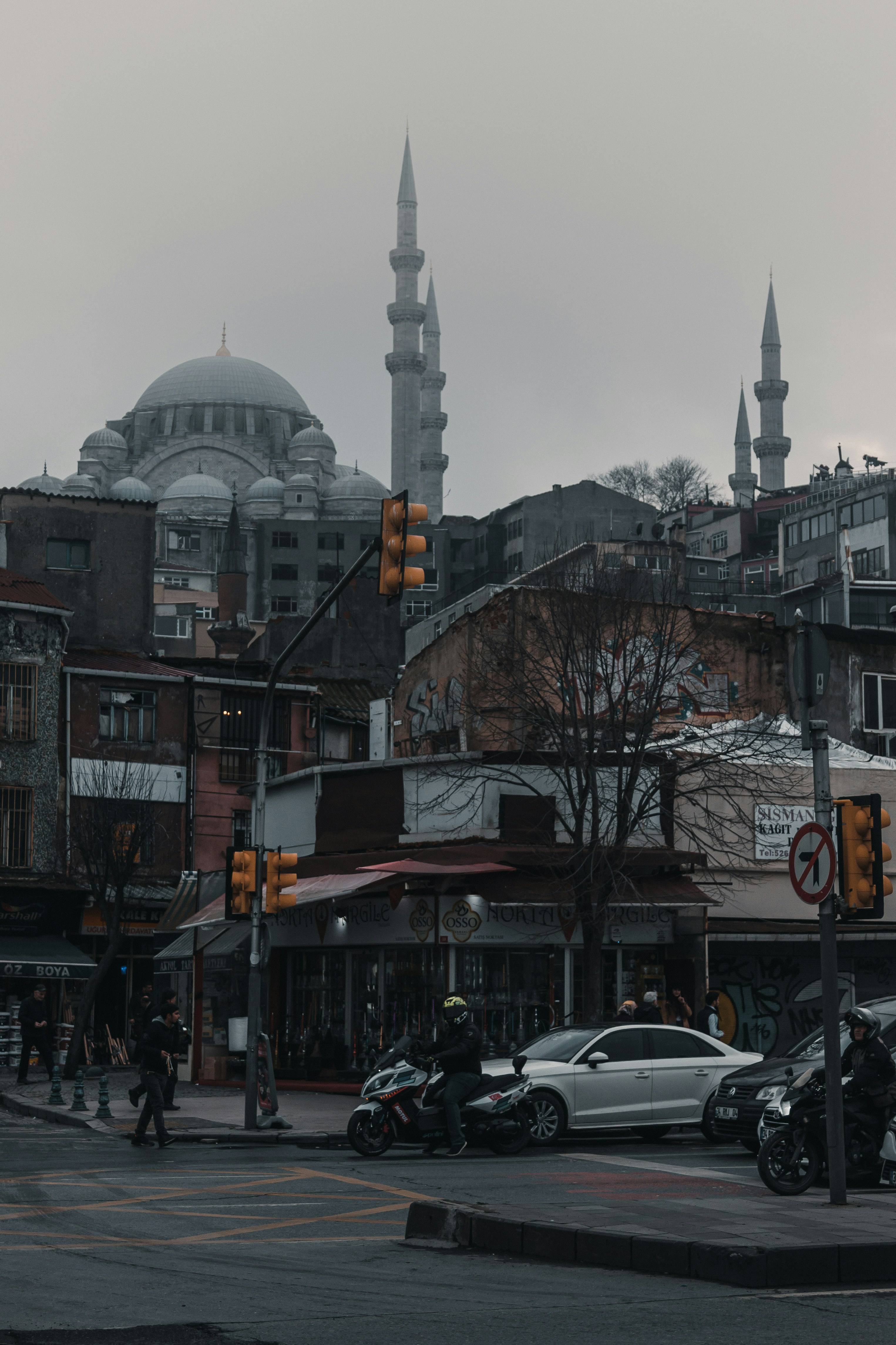 Mist-veiled Istanbul: a domed mosque and twin minarets loom over a busy street