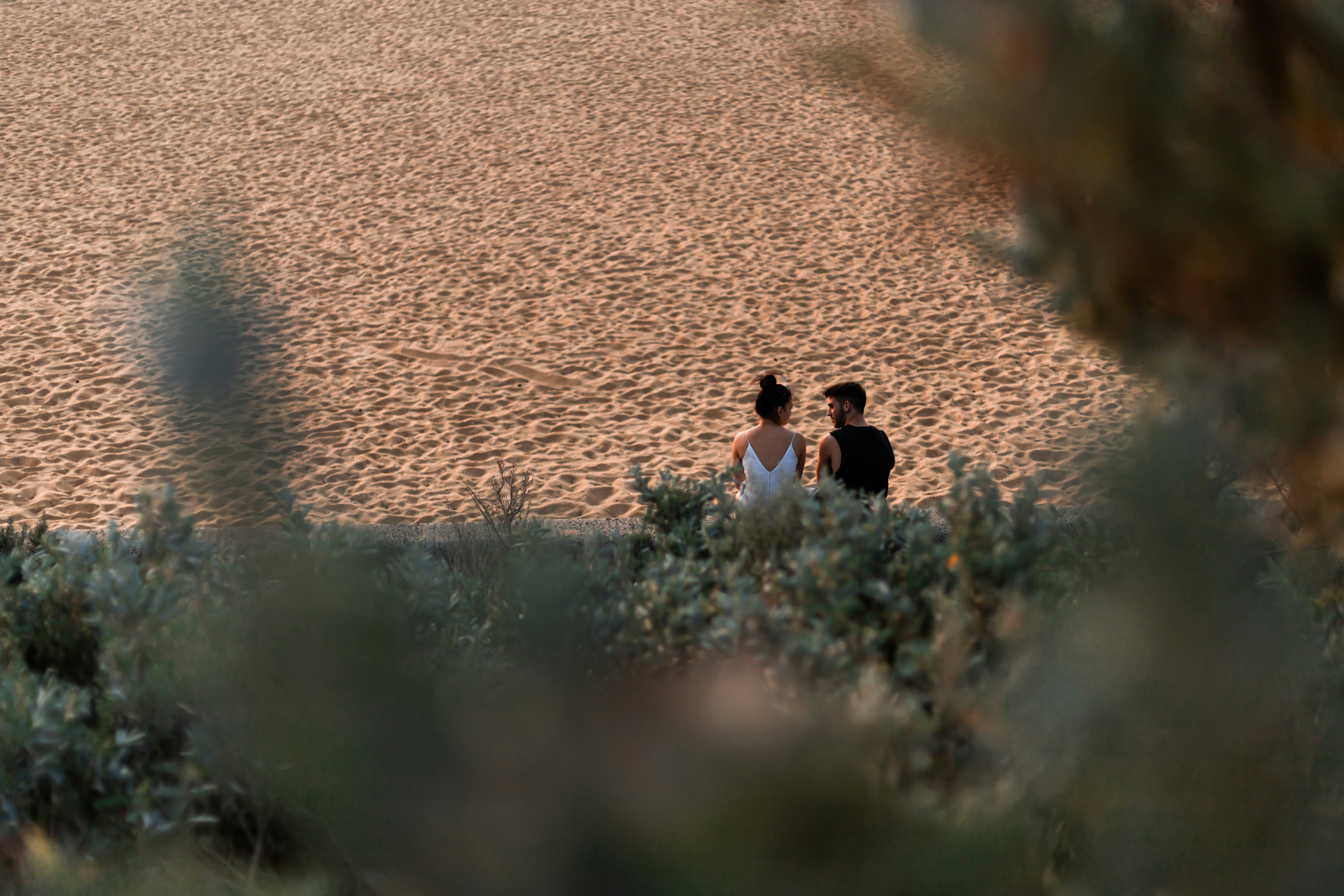 Dune-side Quiet: Two Silhouettes at Golden Hour on a Calm Beach