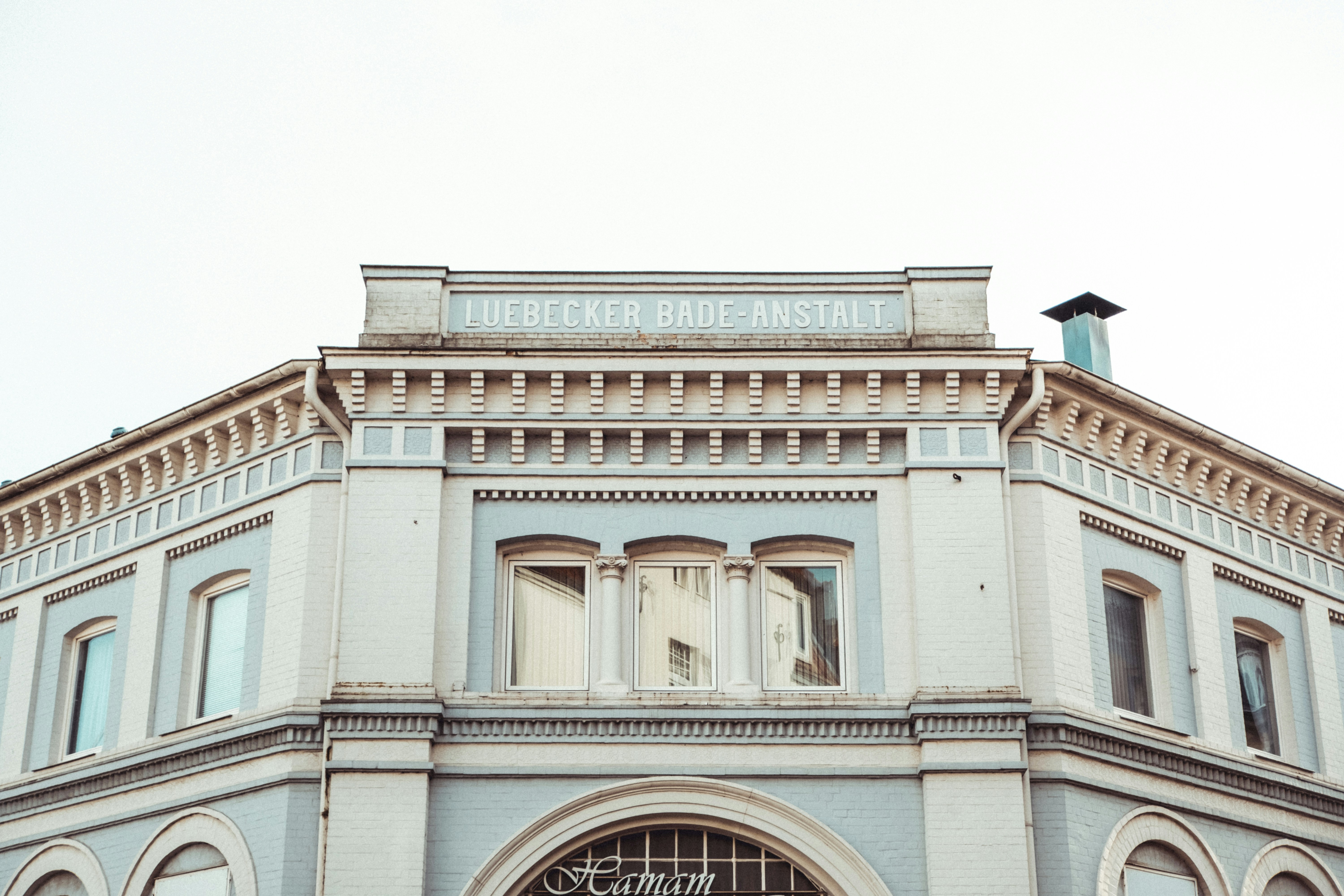 Ornate building facade with classical elements and a soft, muted color palette under an overcast sky.