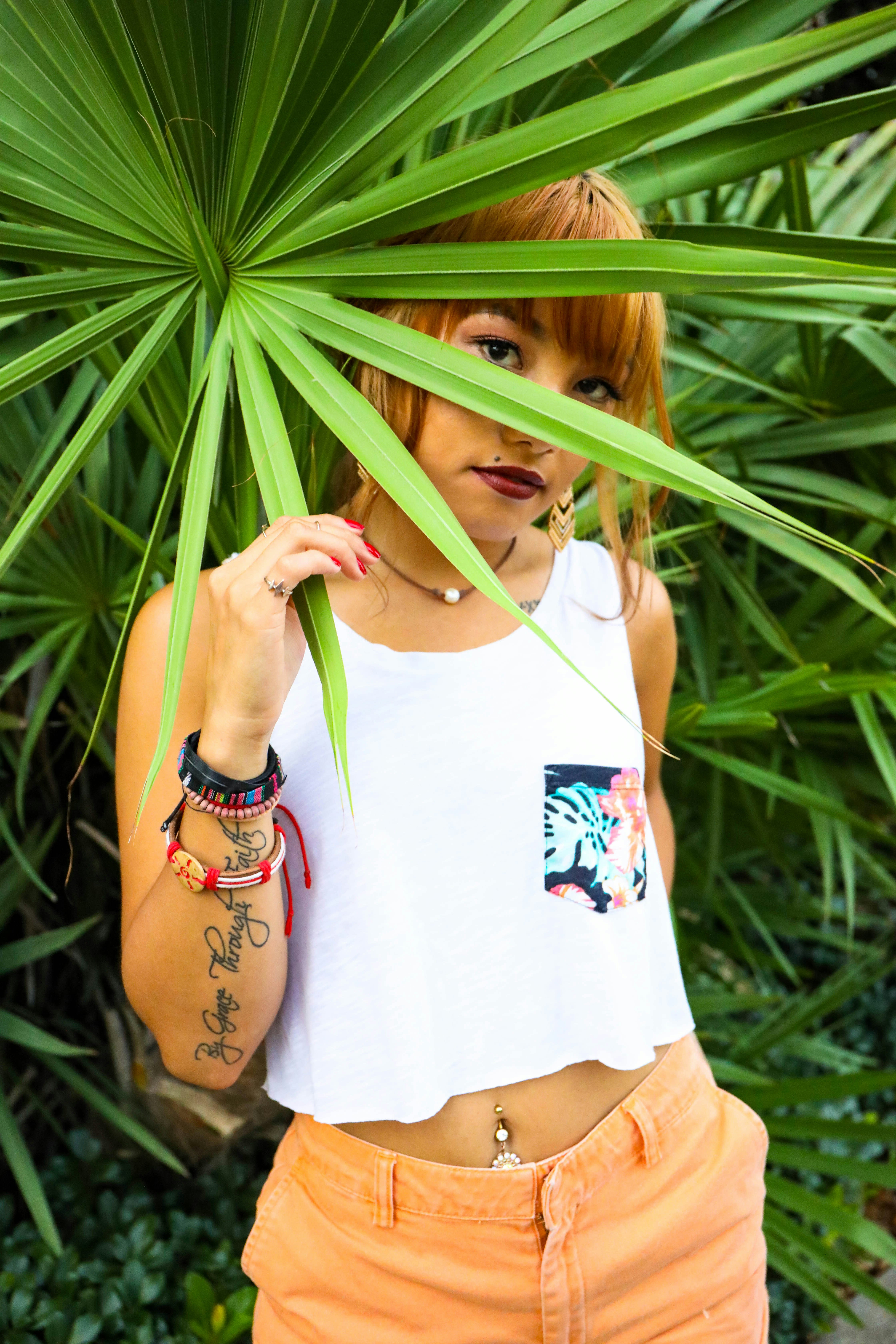 woman in white tank top with green leaves on her left hand