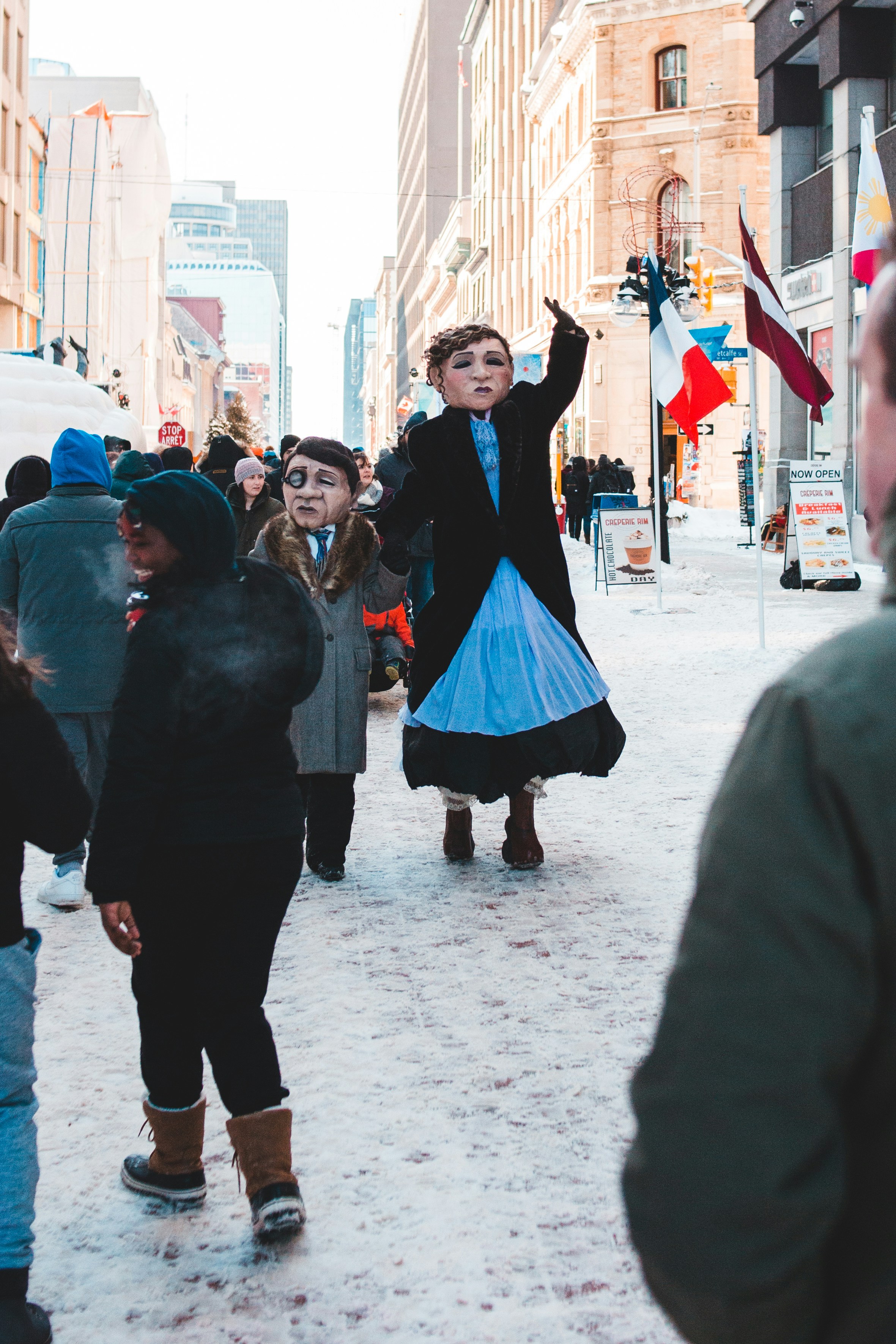 Masked Figure in a Snowy City Parade Reaches Out