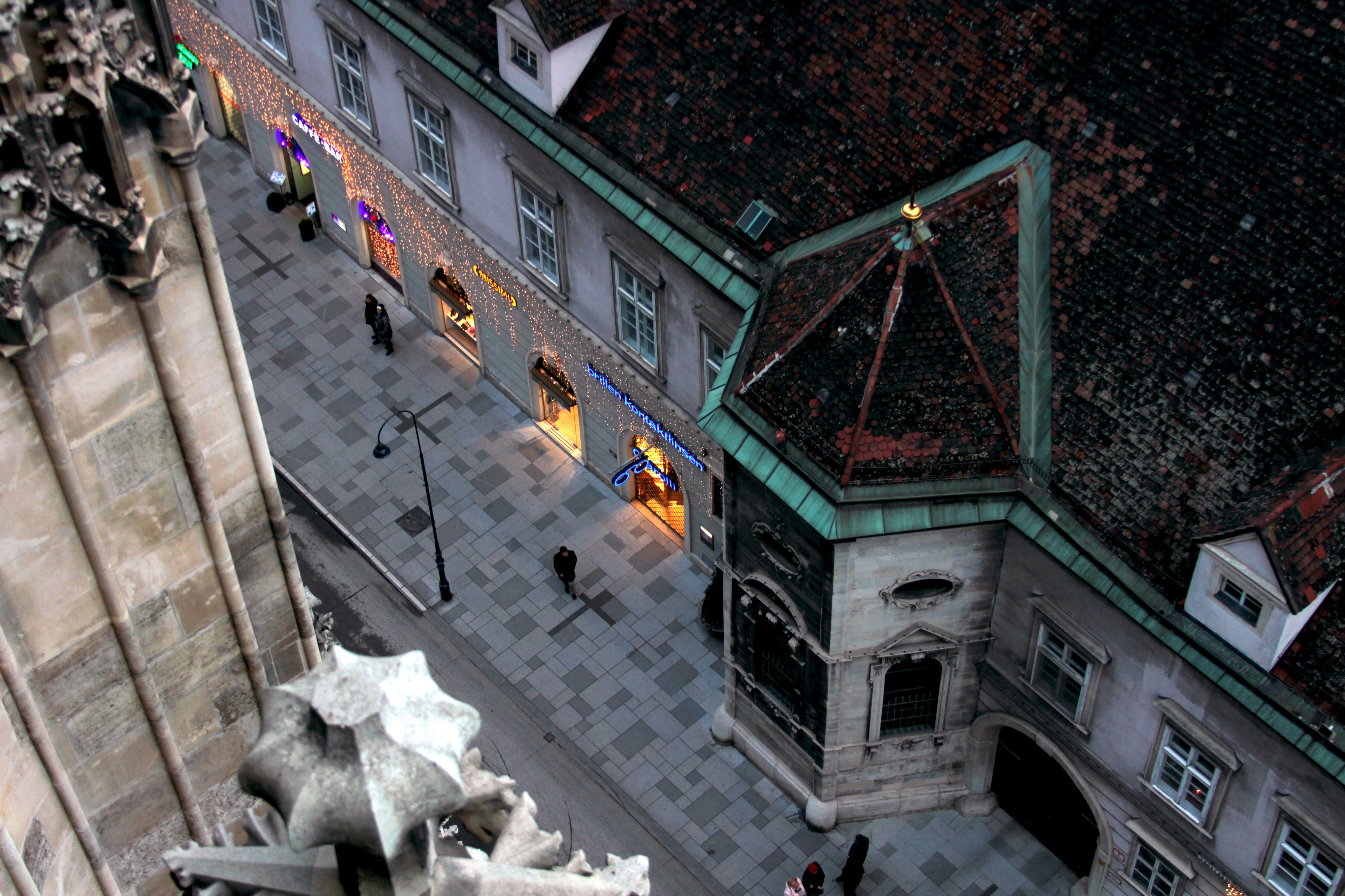 Aerial view of illuminated storefronts along a cobblestone street, showcasing architectural details and evening ambiance.