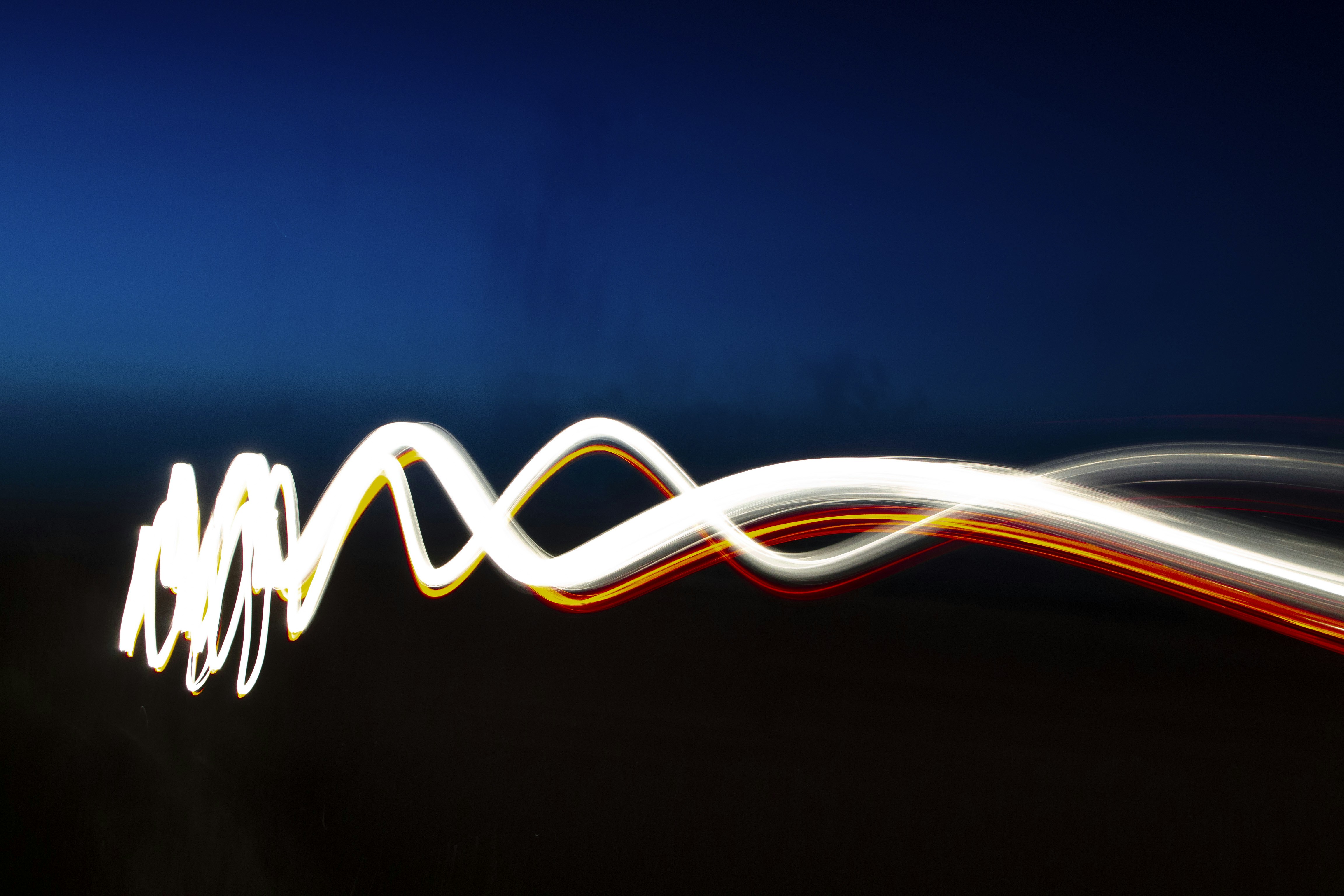Dynamic light trails weaving through a deep blue night sky, showcasing the interplay of motion and illumination.
