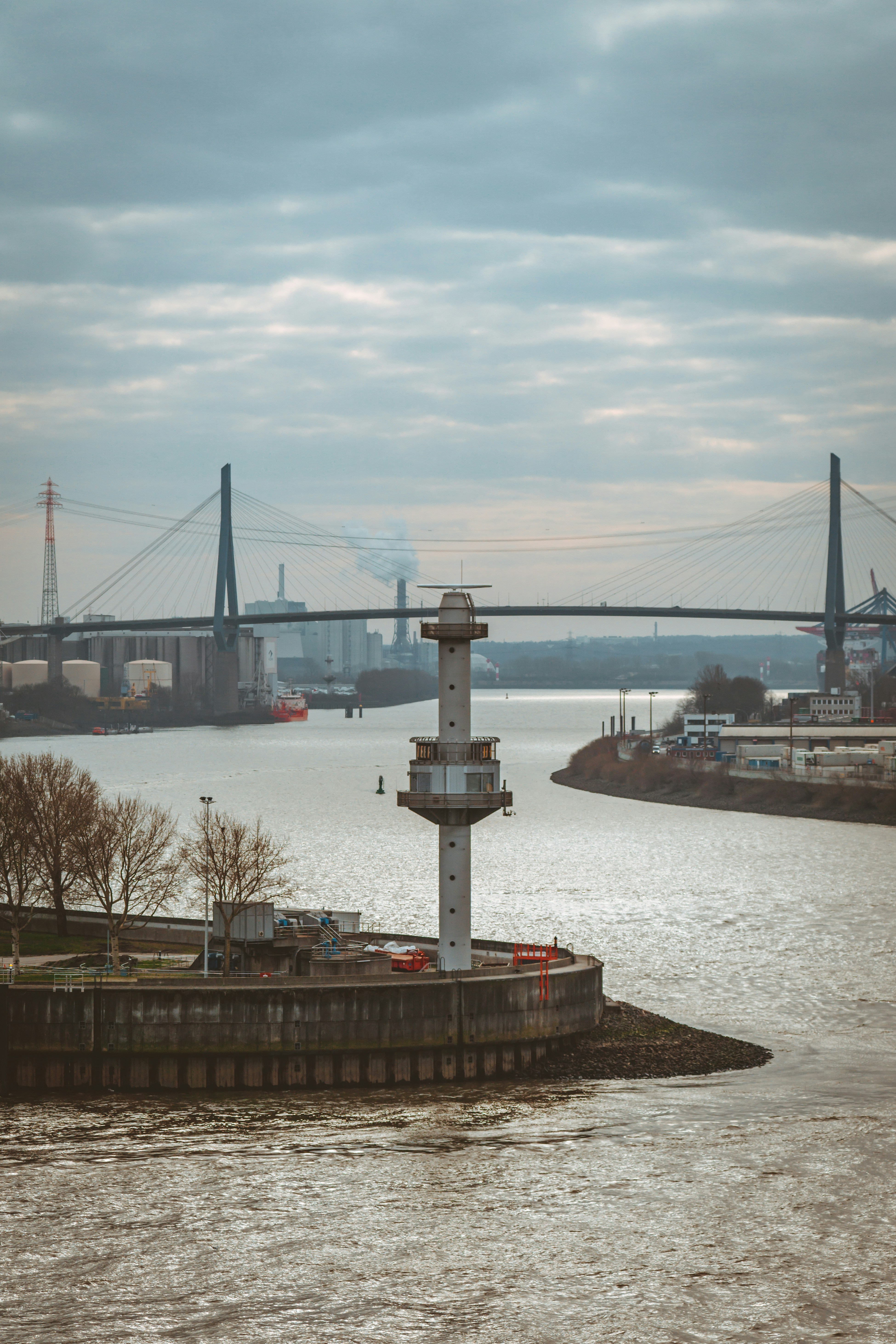 Concrete beacon at the river bend under a distant suspension bridge