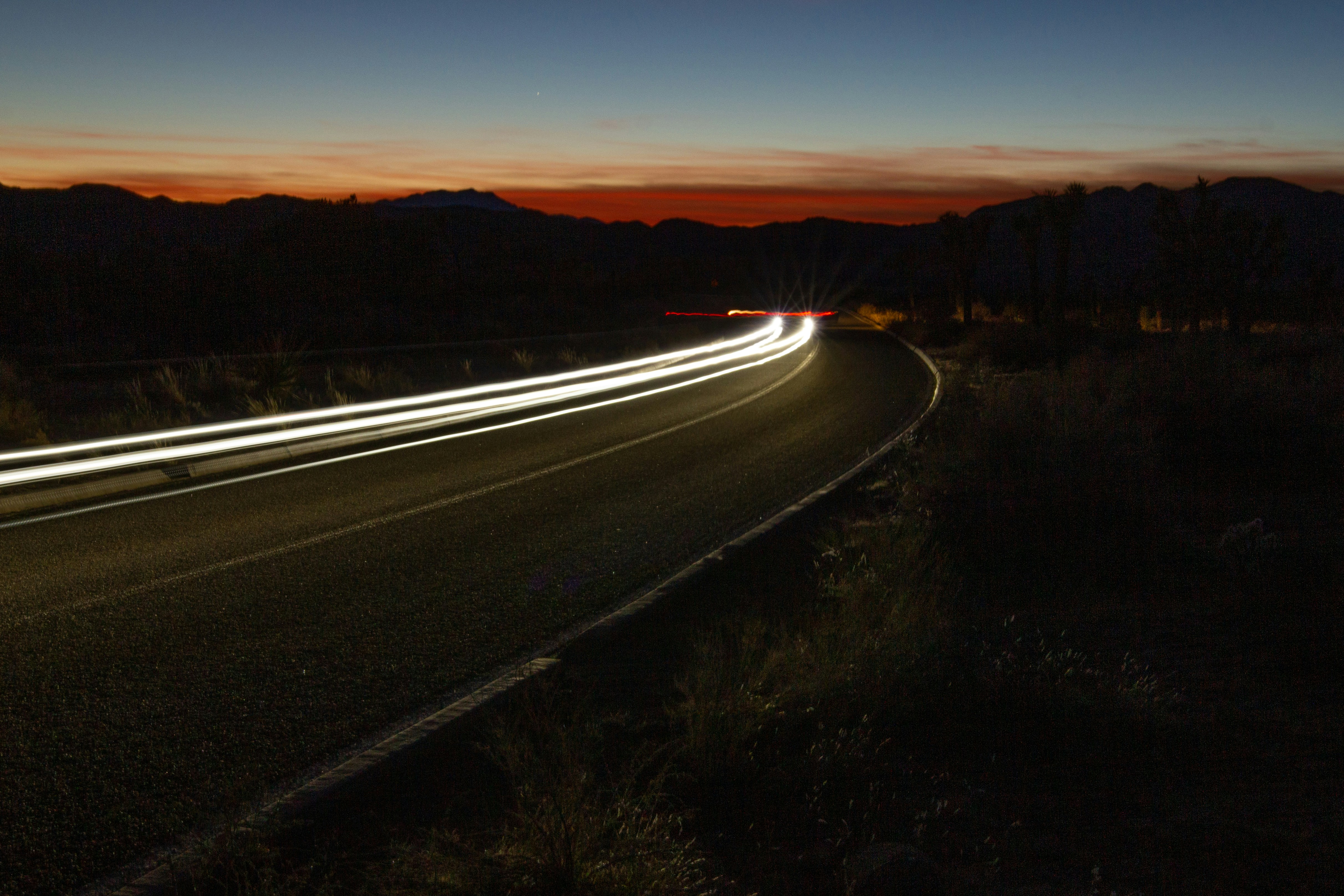 Desert Curve at Dusk: Long-Exposure Tail-Lights Tracing the Highway