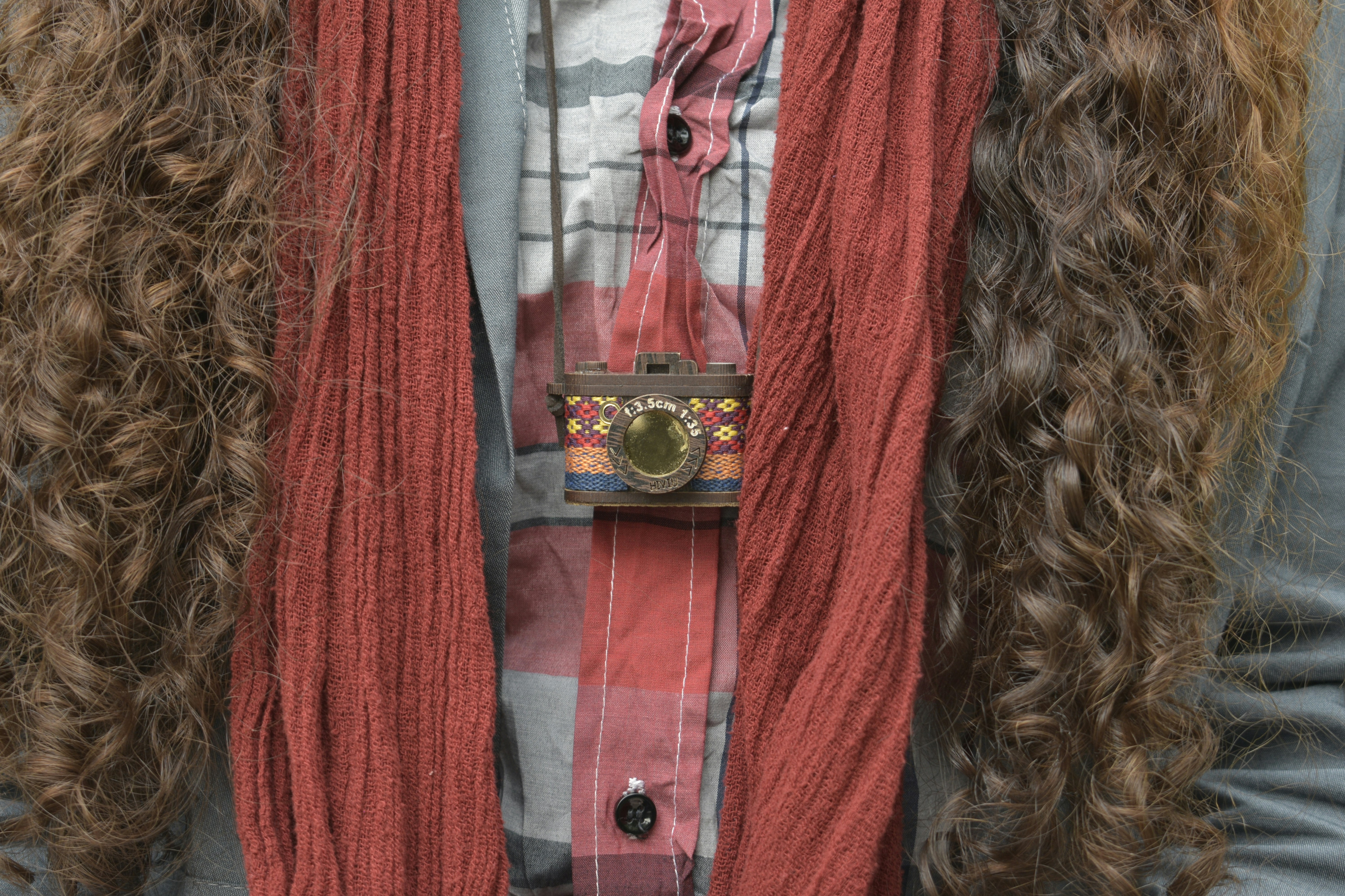 Chest Pendant on Red-Scarfed Person: Textured Detail in Wool and Plaid