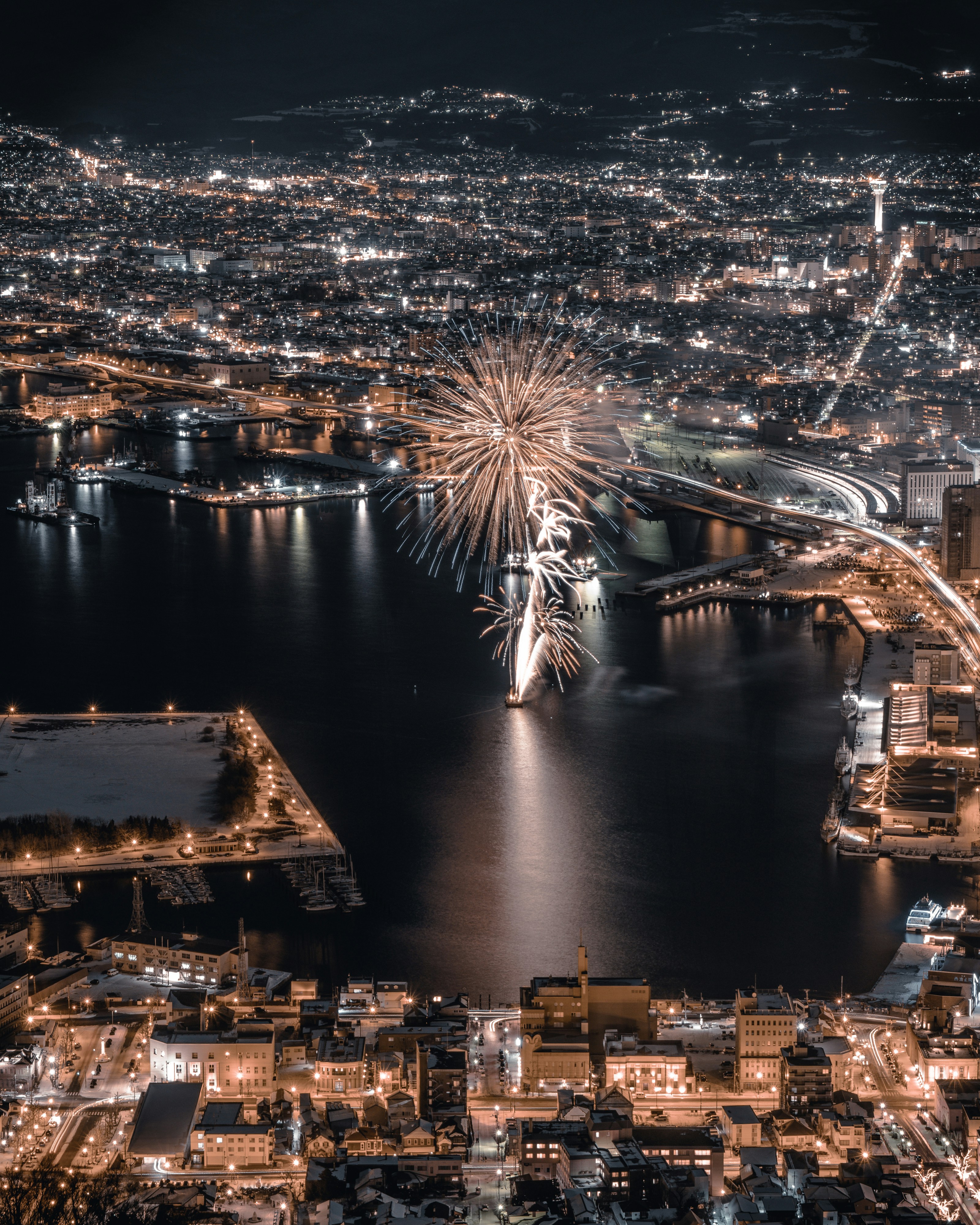 Fireworks explode over the bay at night in Hakodate, Japan. | fireworks display over the city during night time