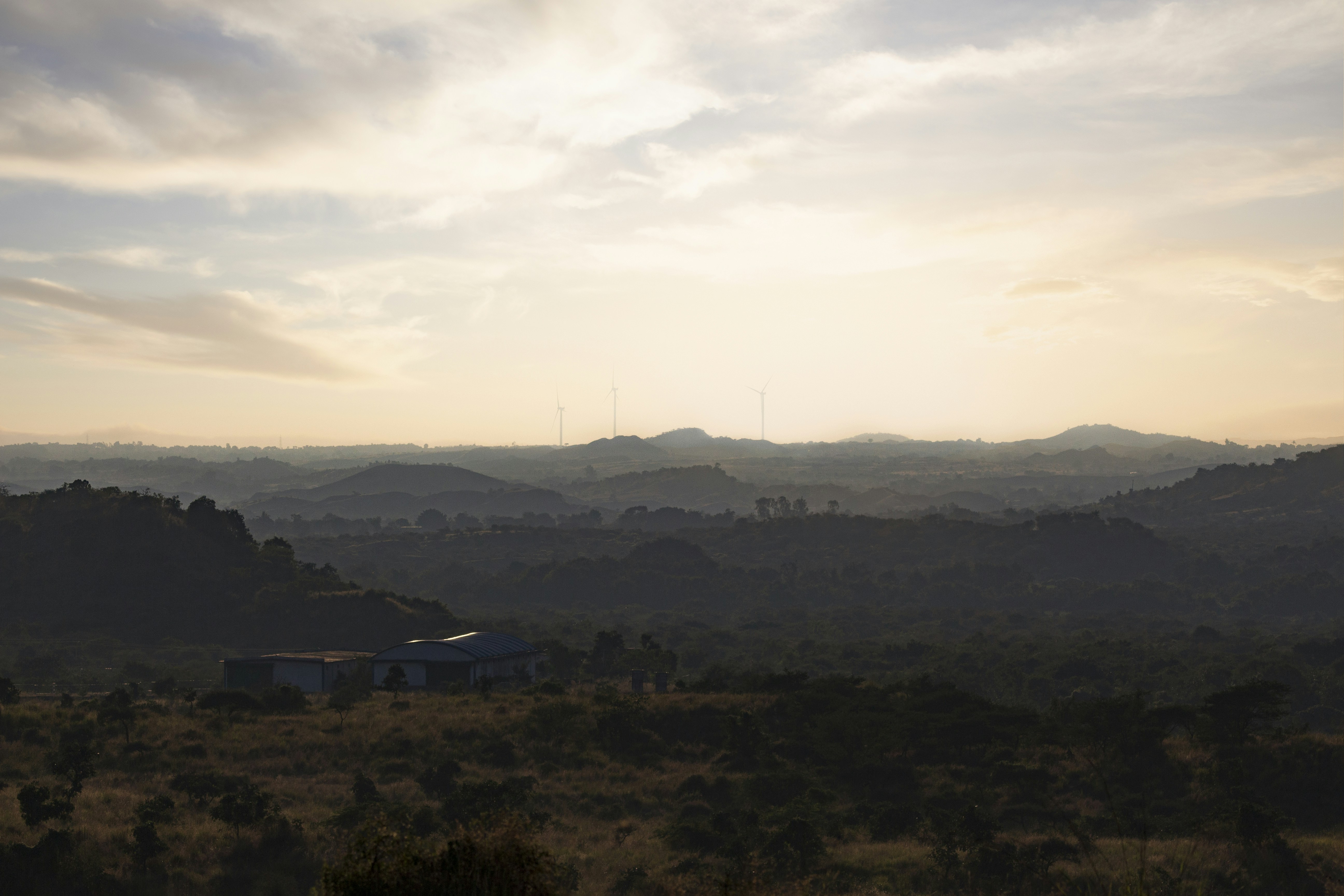 Distant Wind Turbines Across a Hazy Hillside at Sunset