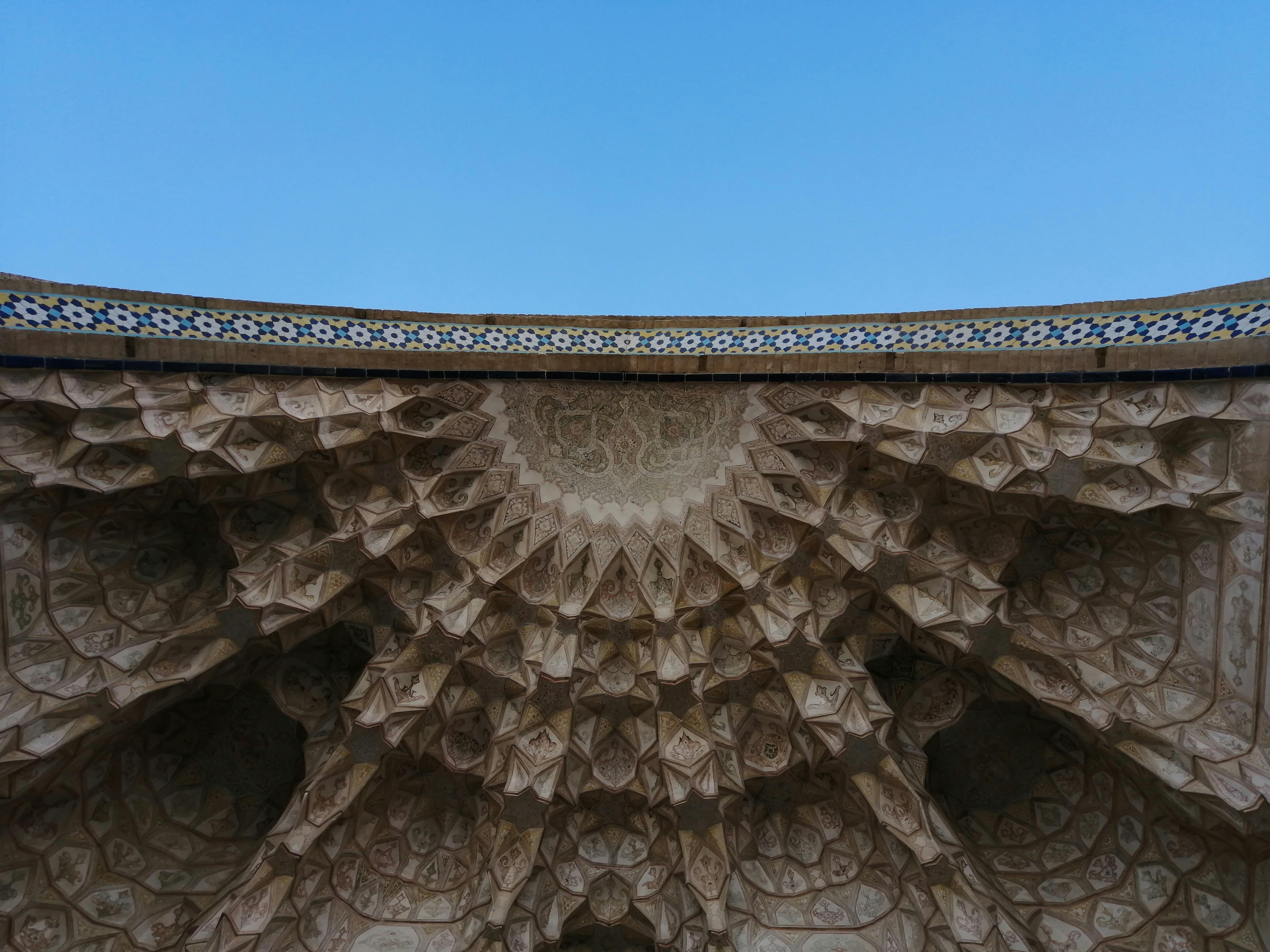 Intricate stone carvings form a symmetrical pattern beneath a clear blue sky.
